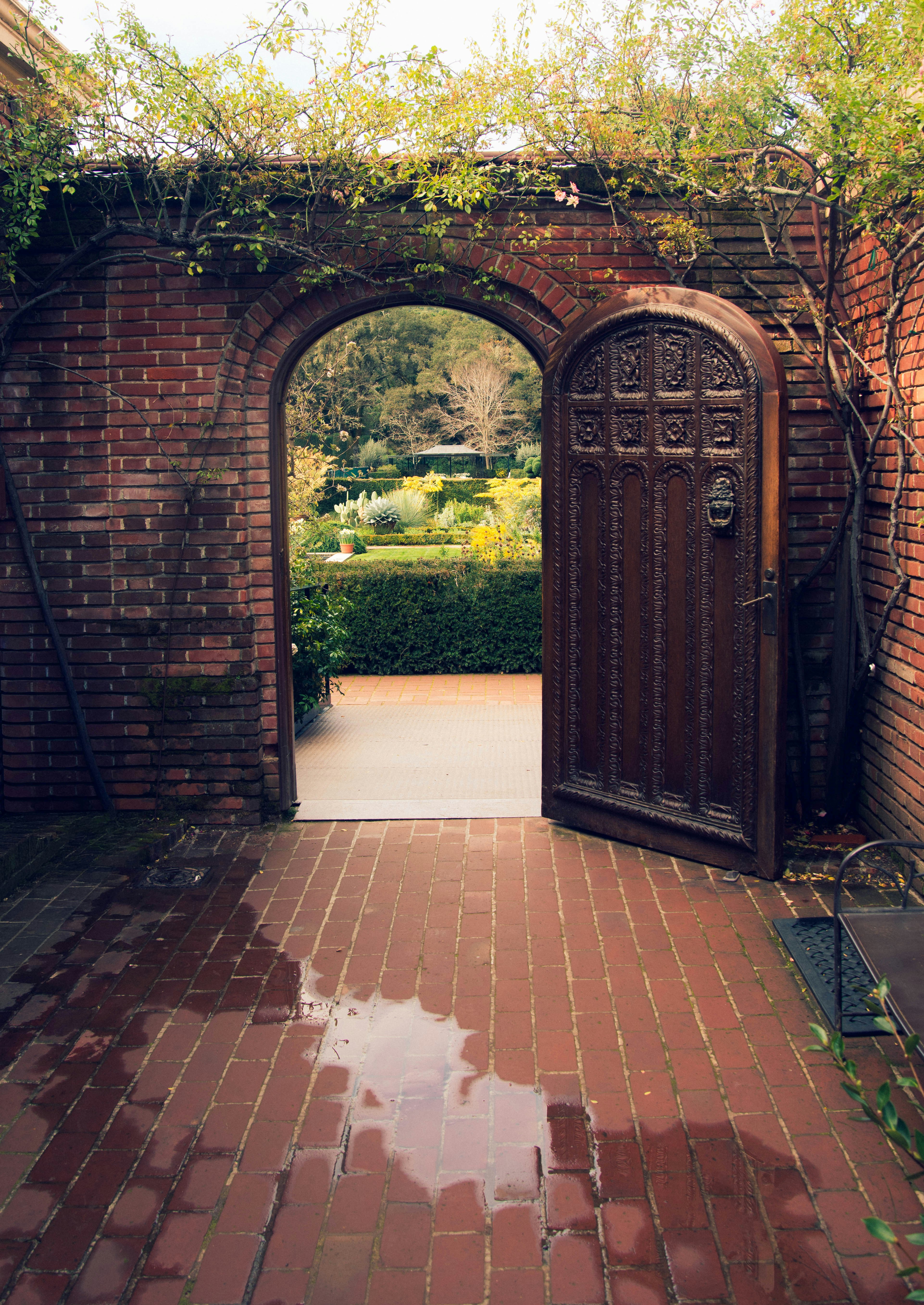 Open Gate to a Sunlit Garden: Brick Archway Framing a Quiet Lawn