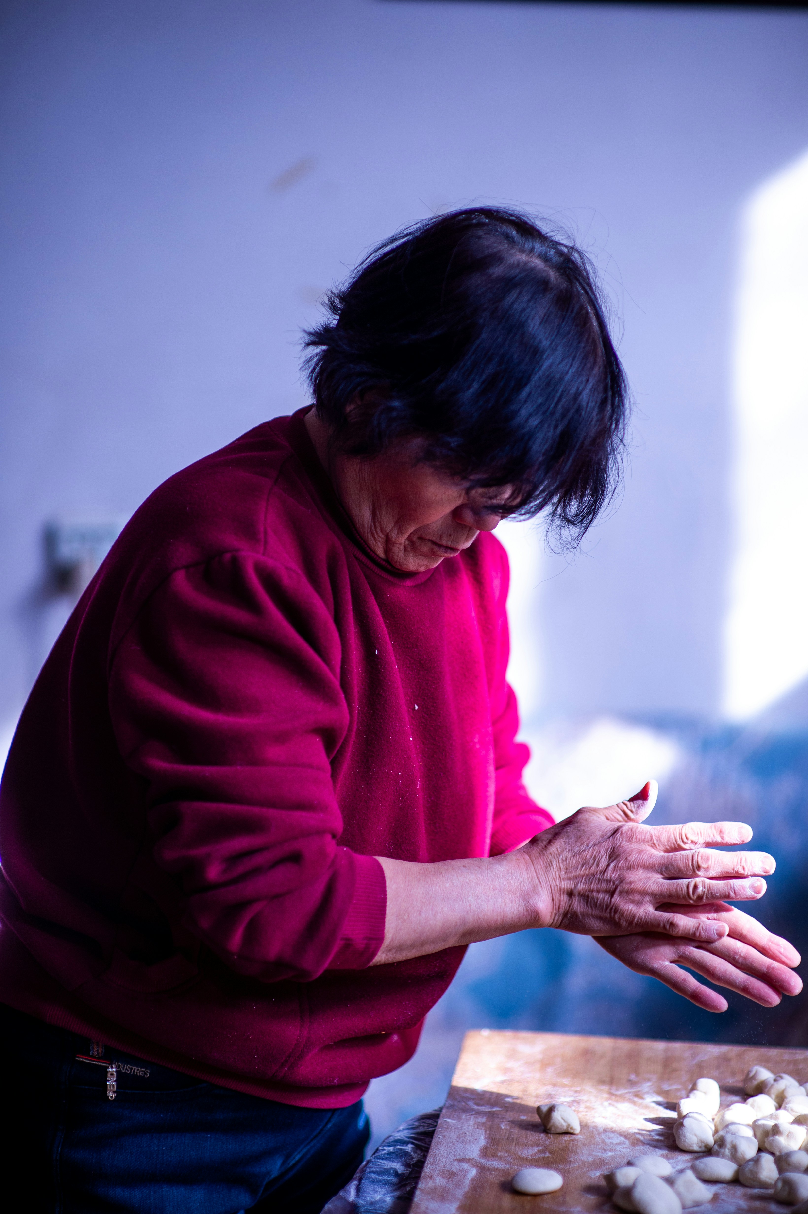 Hands at Work: Dough balls and distant smile beneath a burgundy sweater