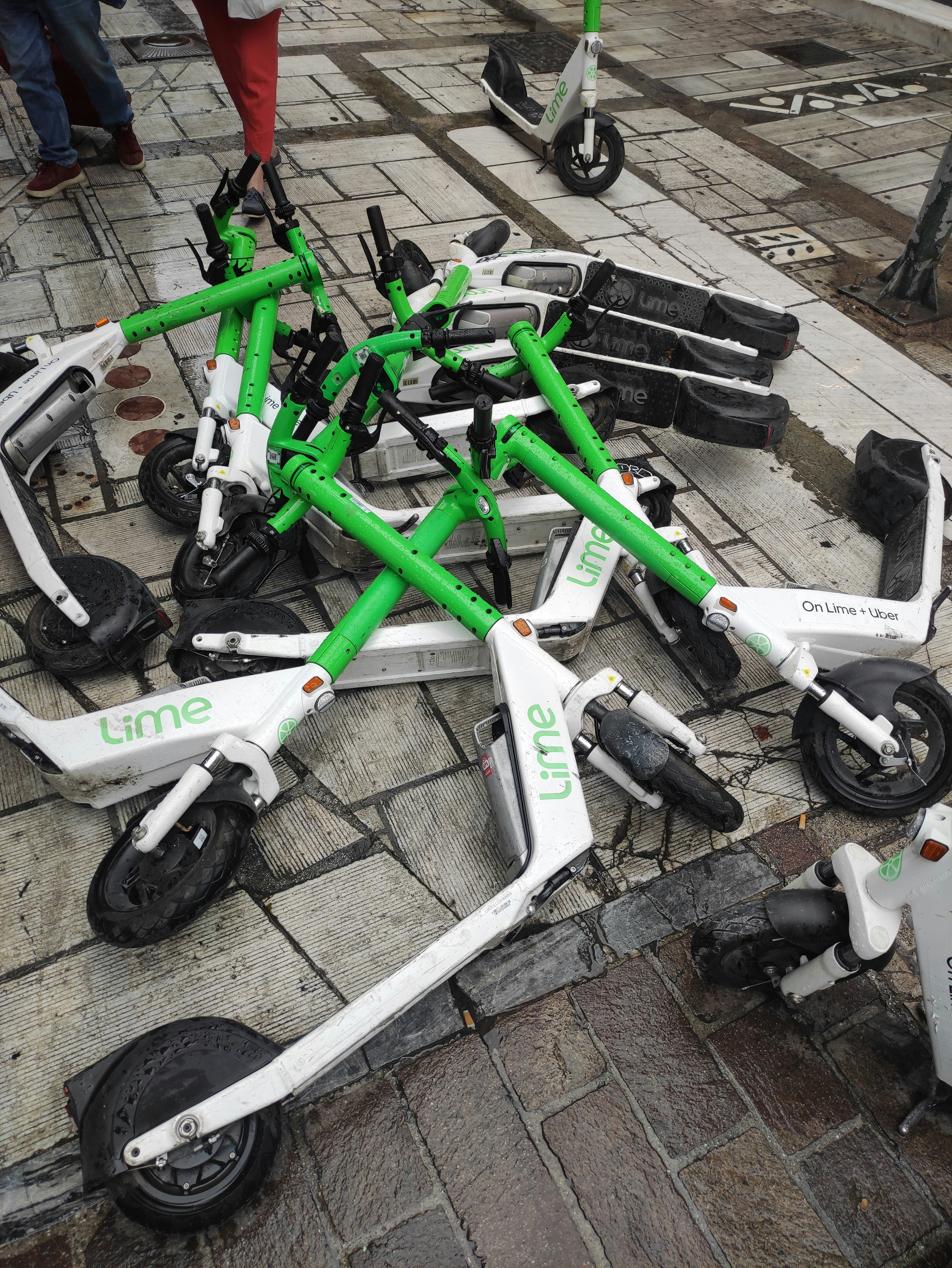 Green and white patterned scooters piled carelessly on a street in the historic center of Athens, Greece, reflecting urban mobility and city life.