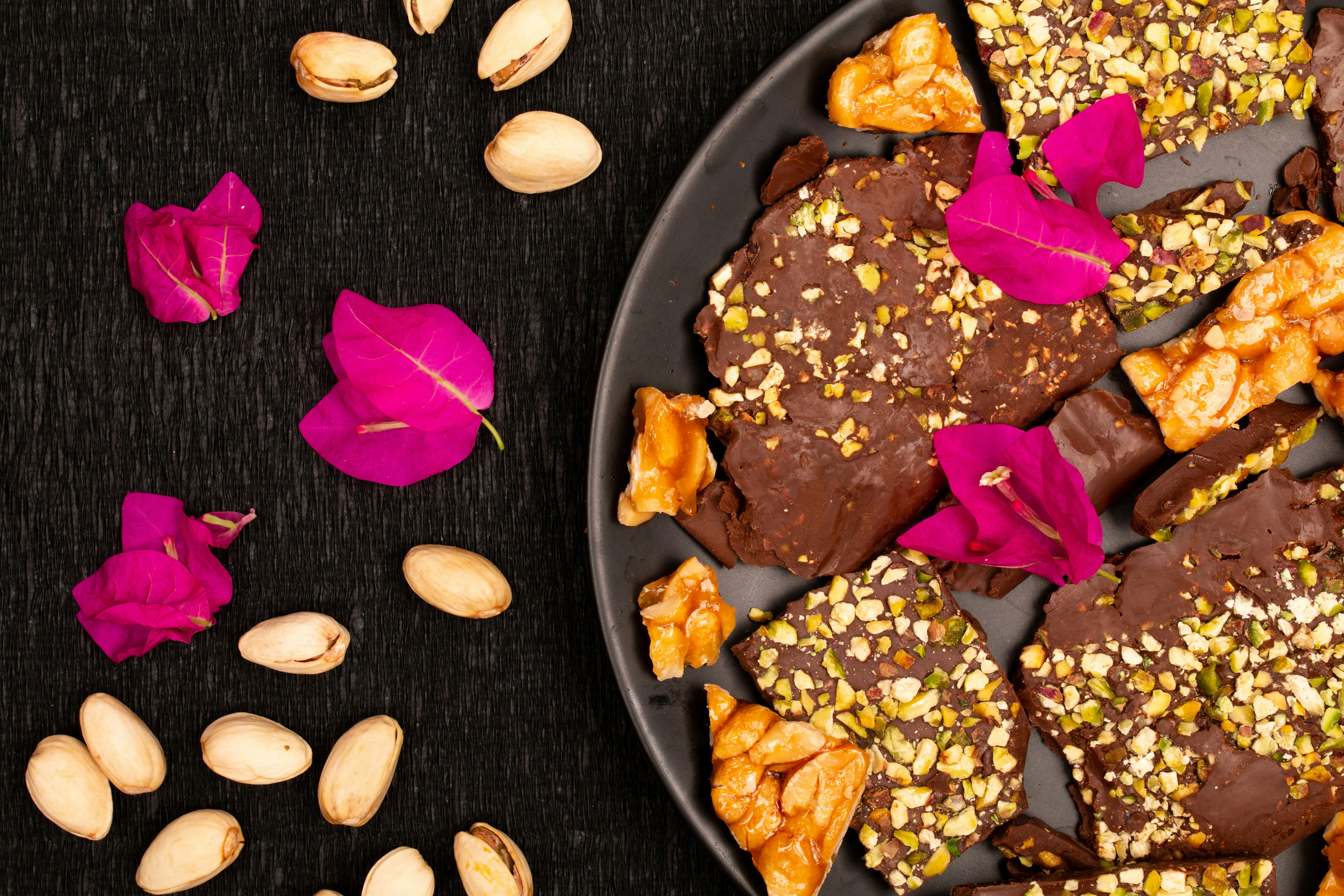 Almond-coated chocolate brittle fragments with fuchsia petals