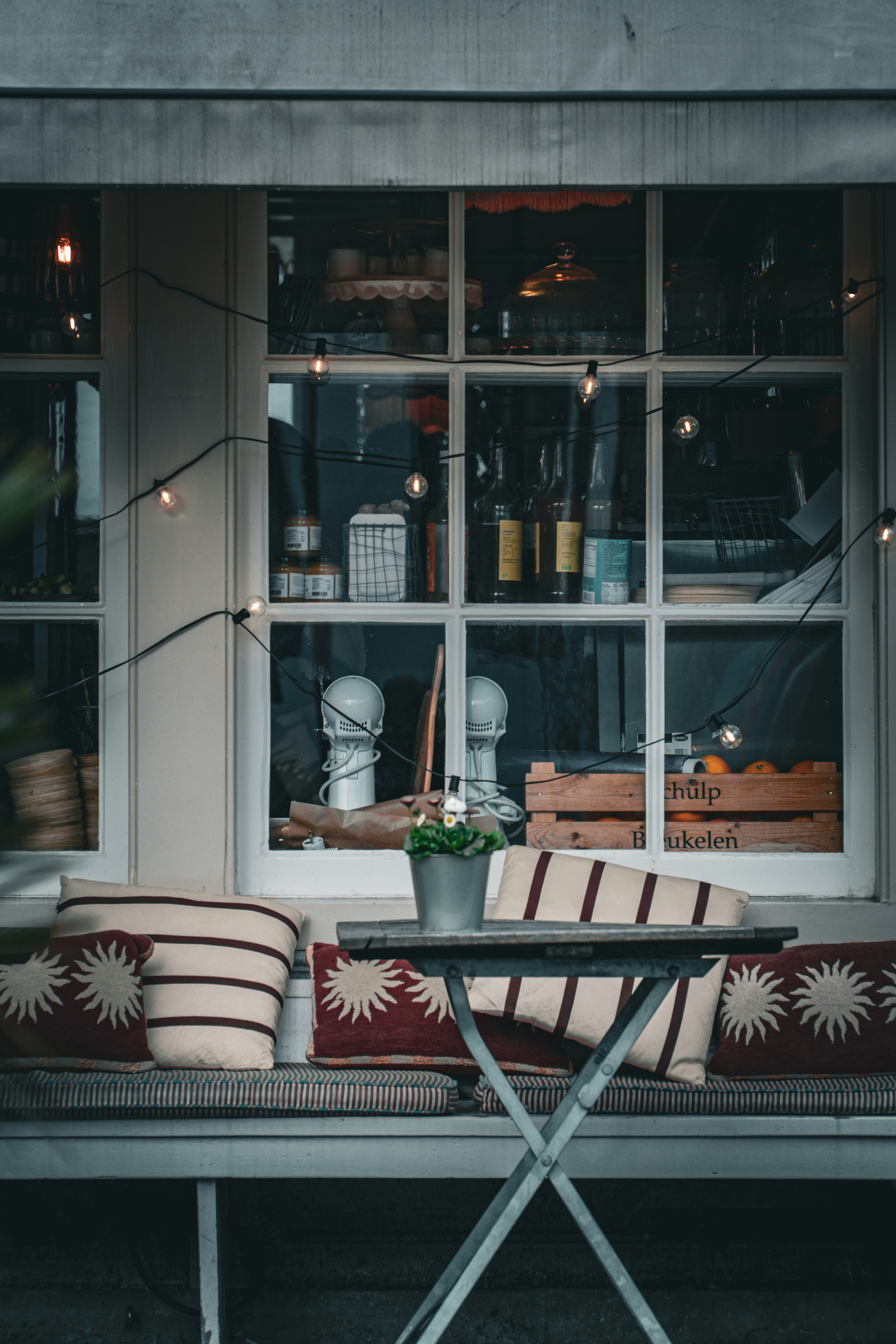 Cozy Display: string lights, potted plant, and café wares in a window-converted seating nook
