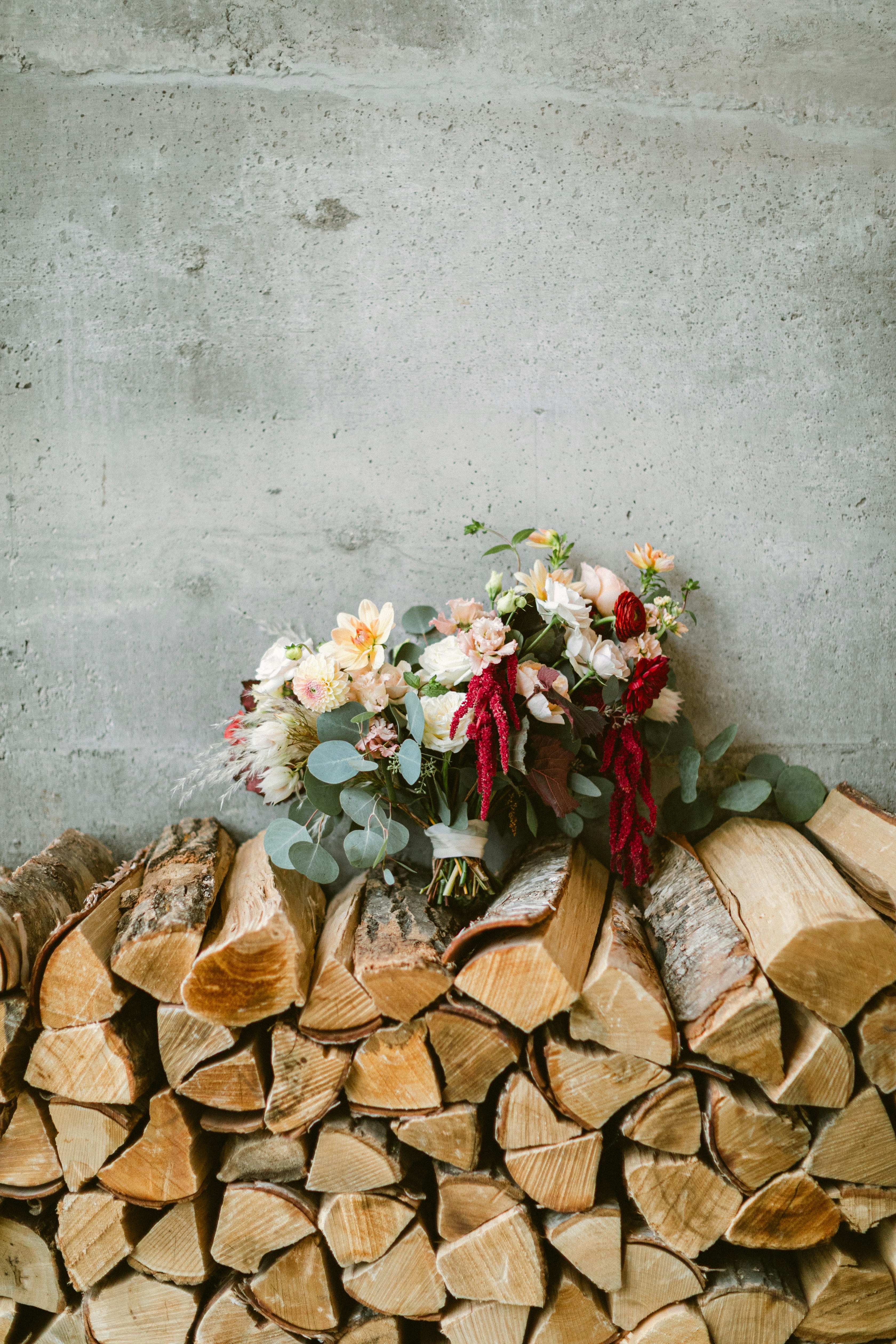 Bouquet resting on a stacked firewood backdrop beneath a minimalist concrete wall