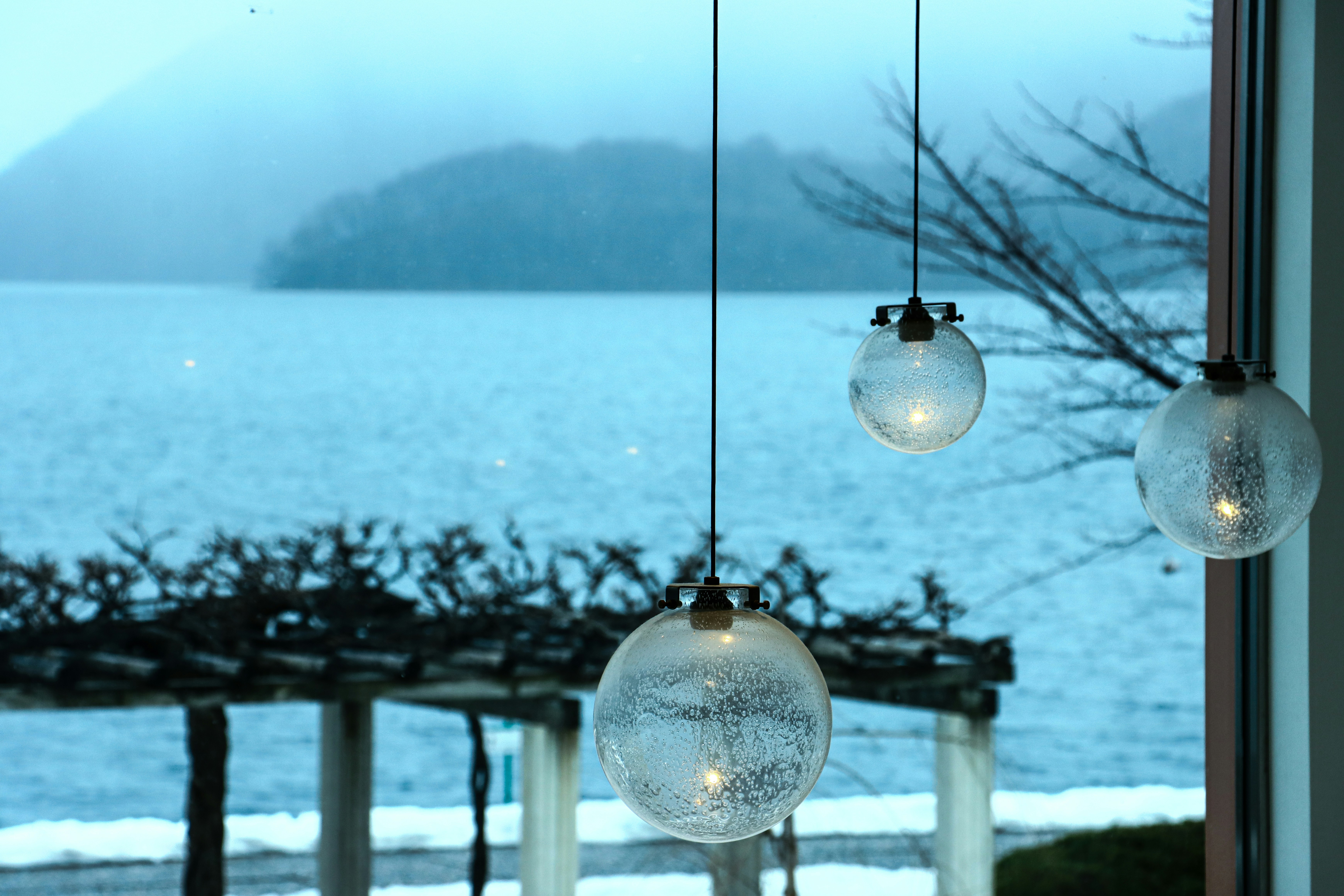 Three Glass Orbs Hover Over a Quiet Lakeside Window