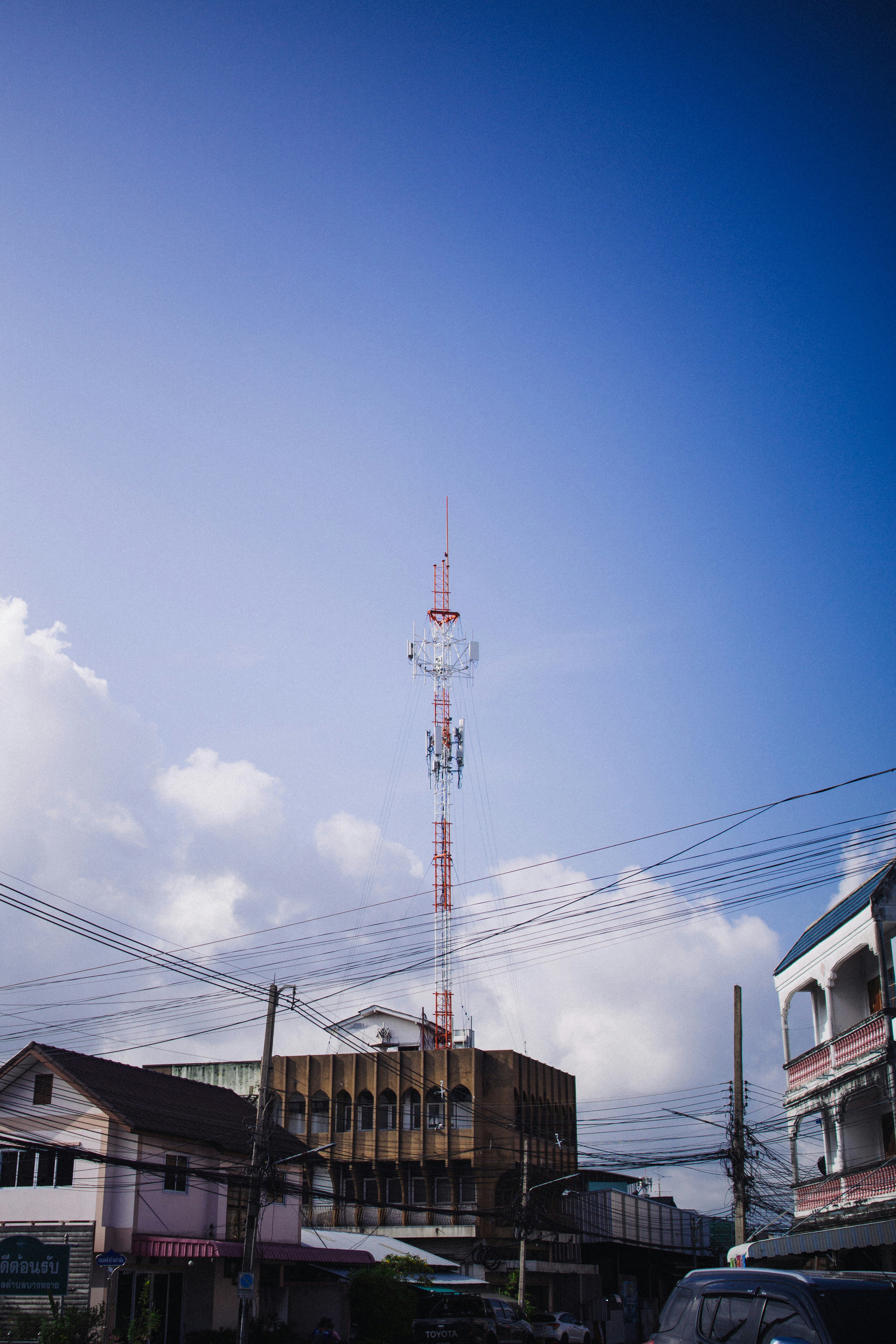 Broadcast Tower Reaching Toward a Clear Sky Over a Quiet Street