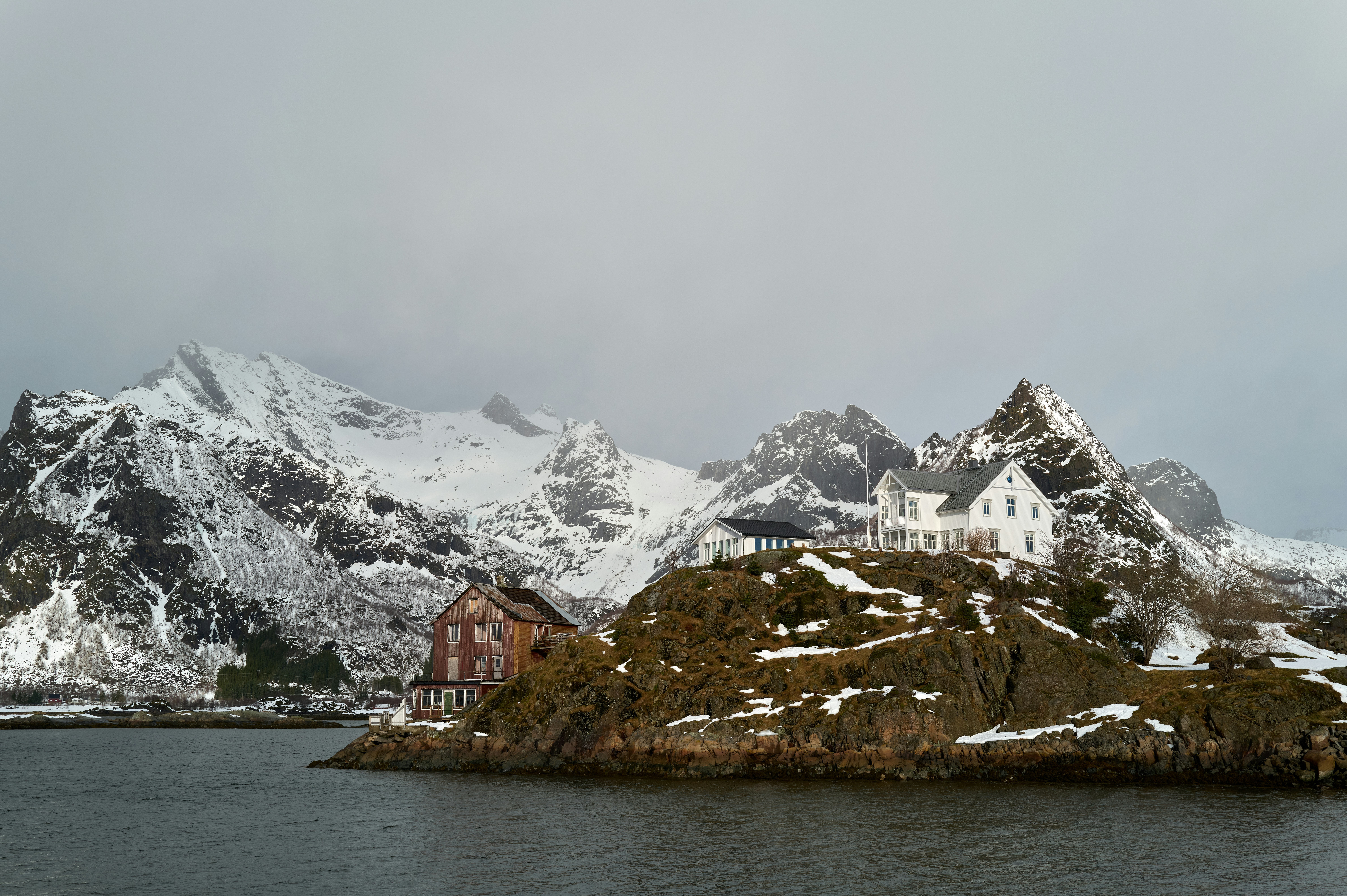 Snow-kissed Coastal Village Beside Jagged Peaks