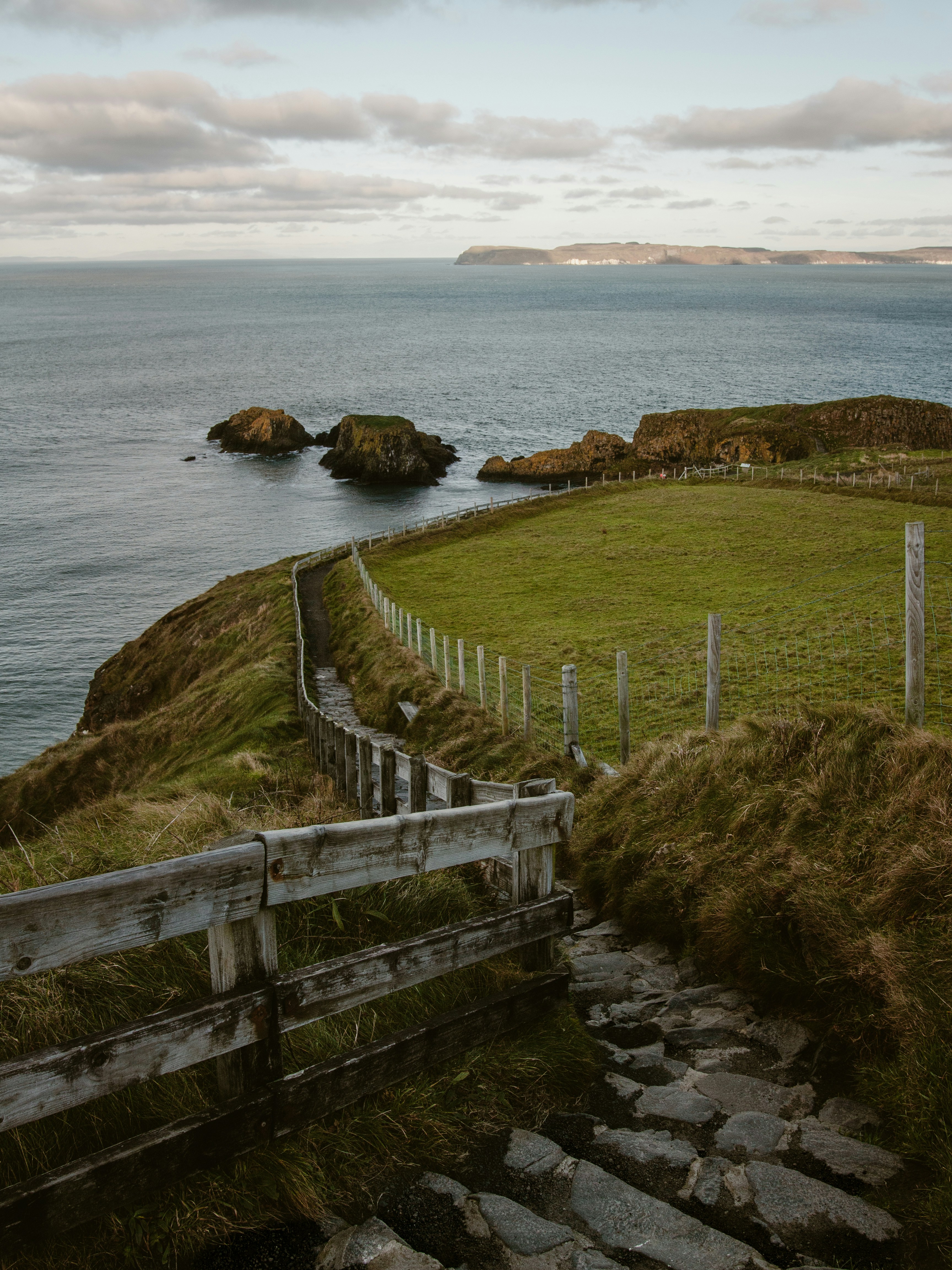 Weathered path along a grassy coastline toward a distant shoreline