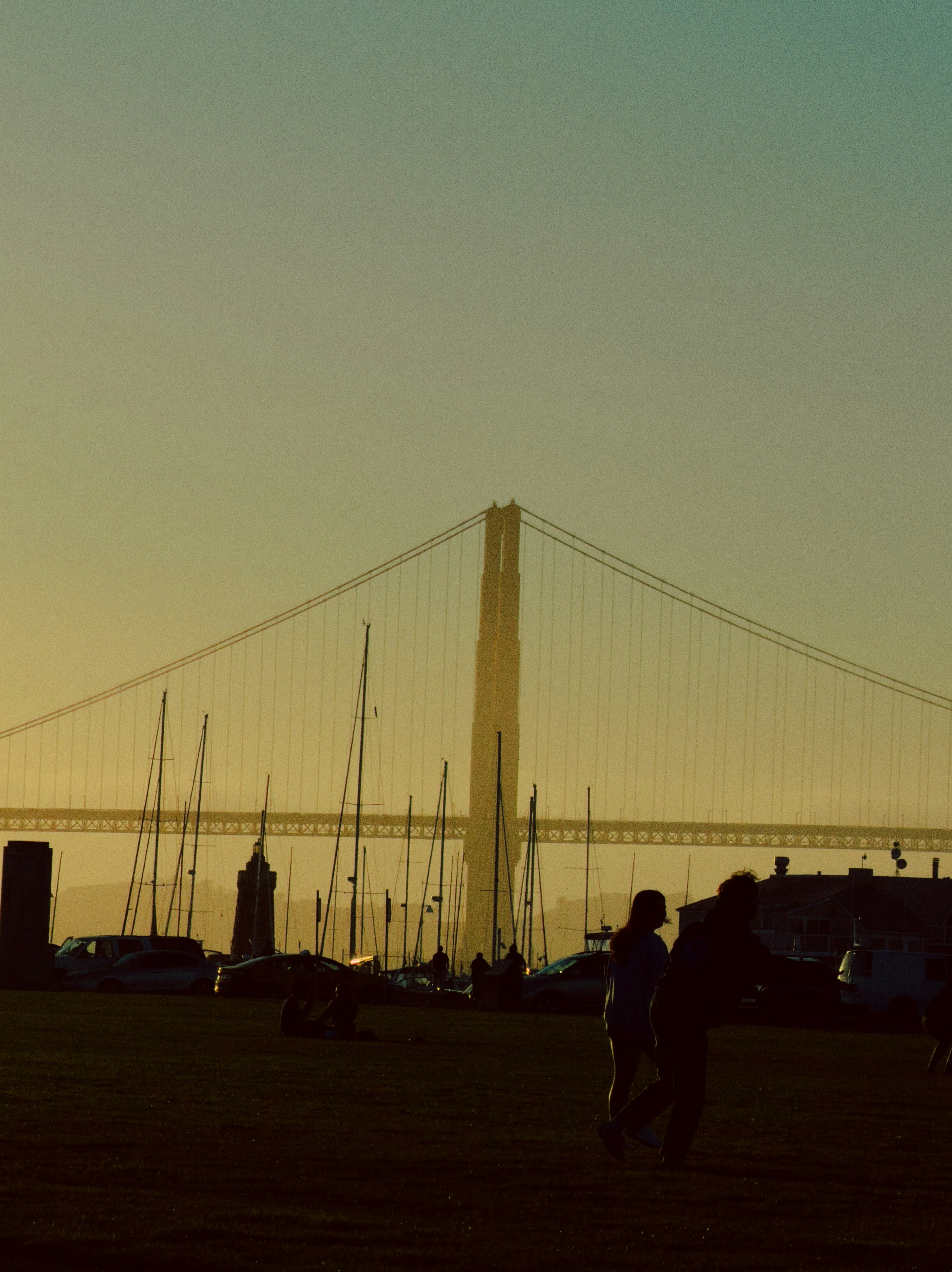 Golden Hour by the Pier: Boats, Silhouettes, and a Suspended Bridge