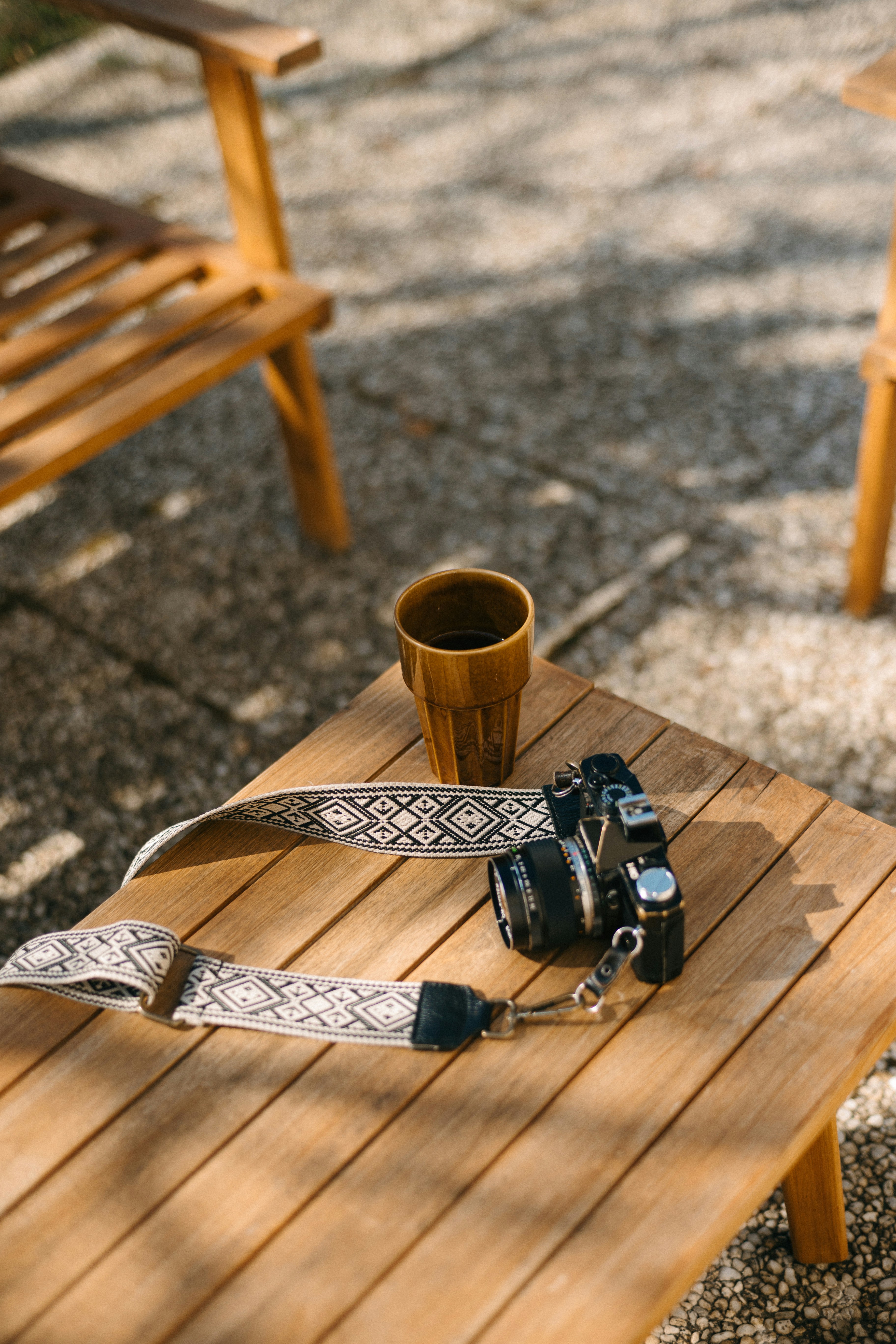 Camera on Wooden Table: A Rustic Shot of a Vintage Canon with Strap and Cup