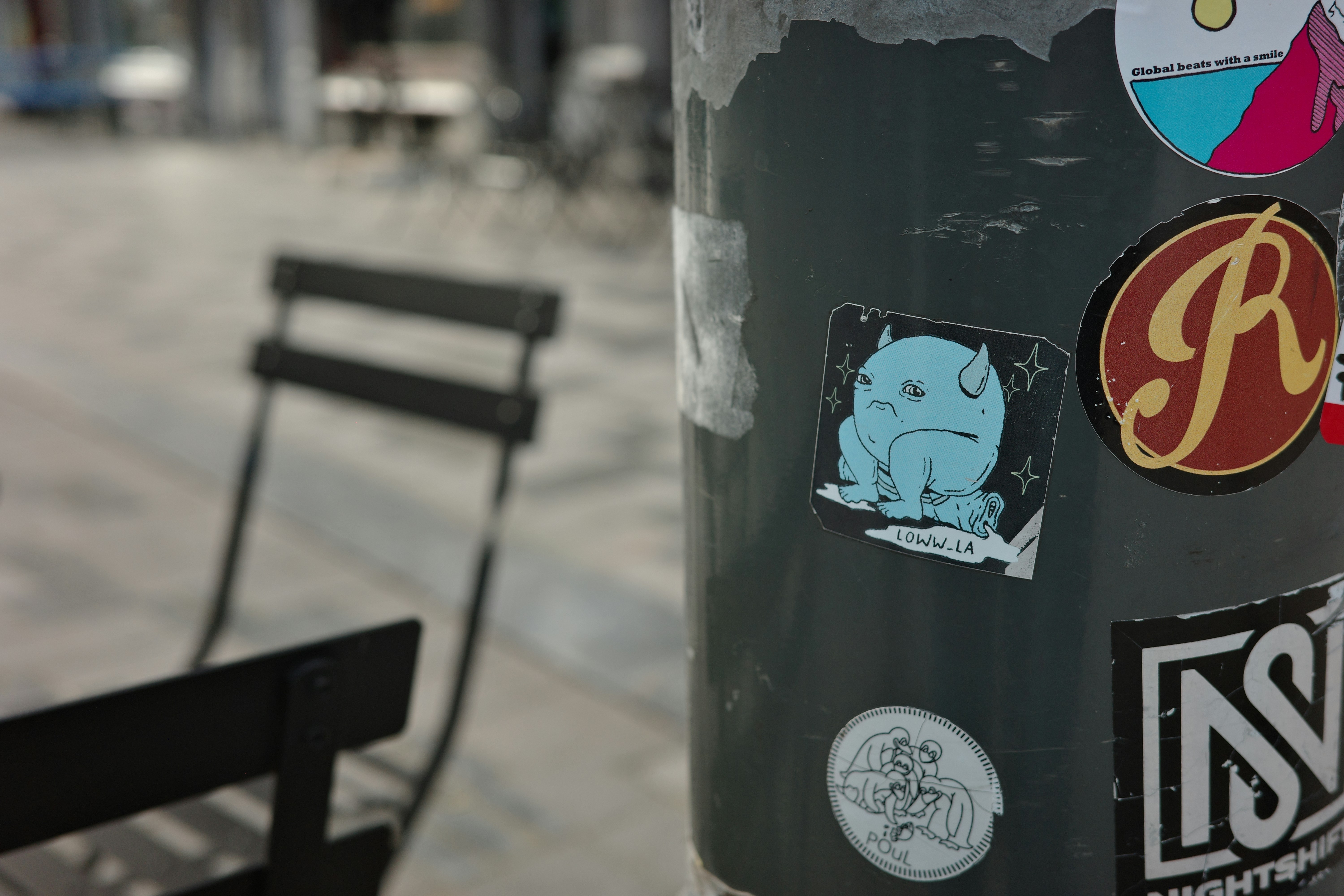 Stickered utility pole in an urban plaza