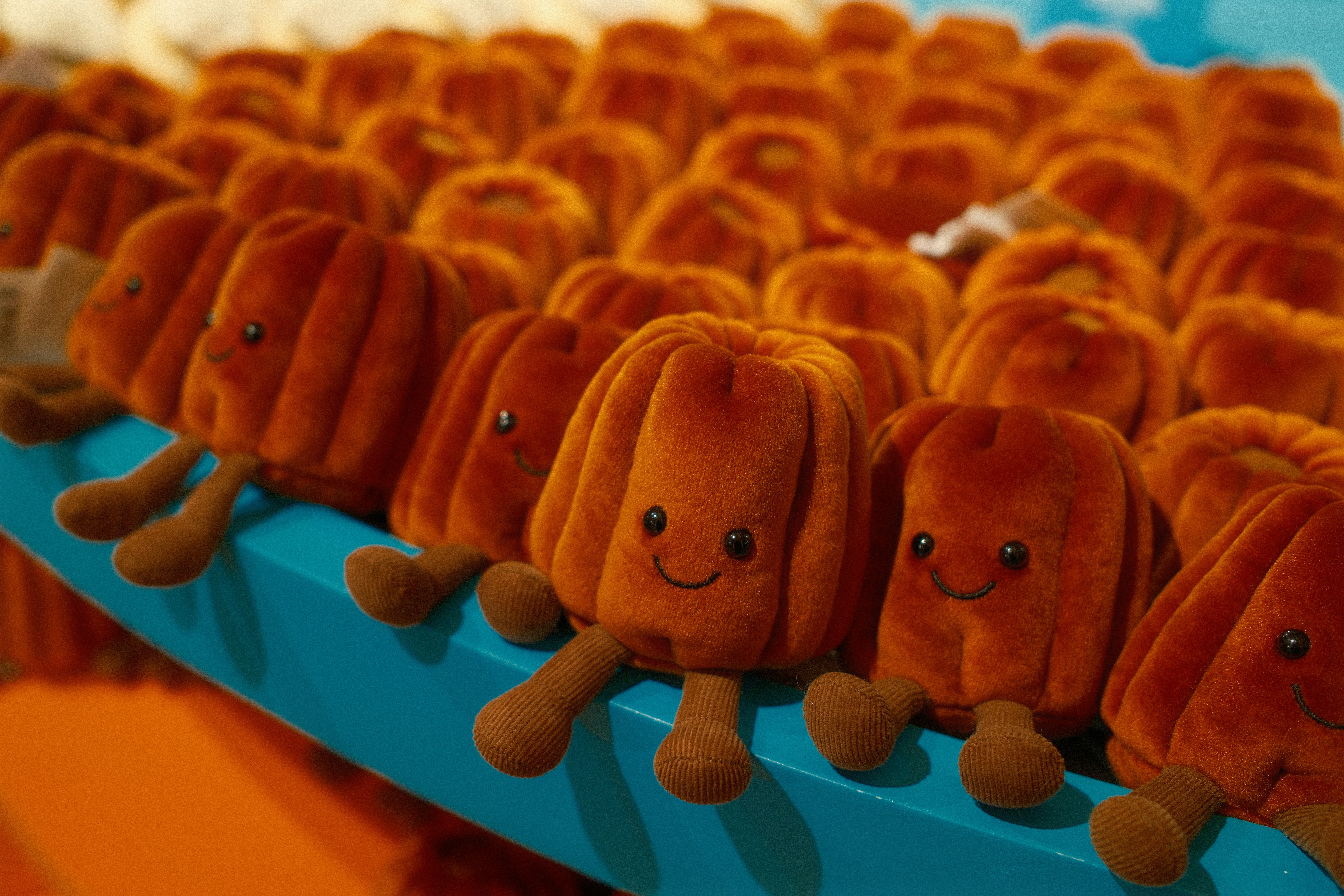 Row of Plush Banana-Bunny Toys on a Bright Turquoise Tray