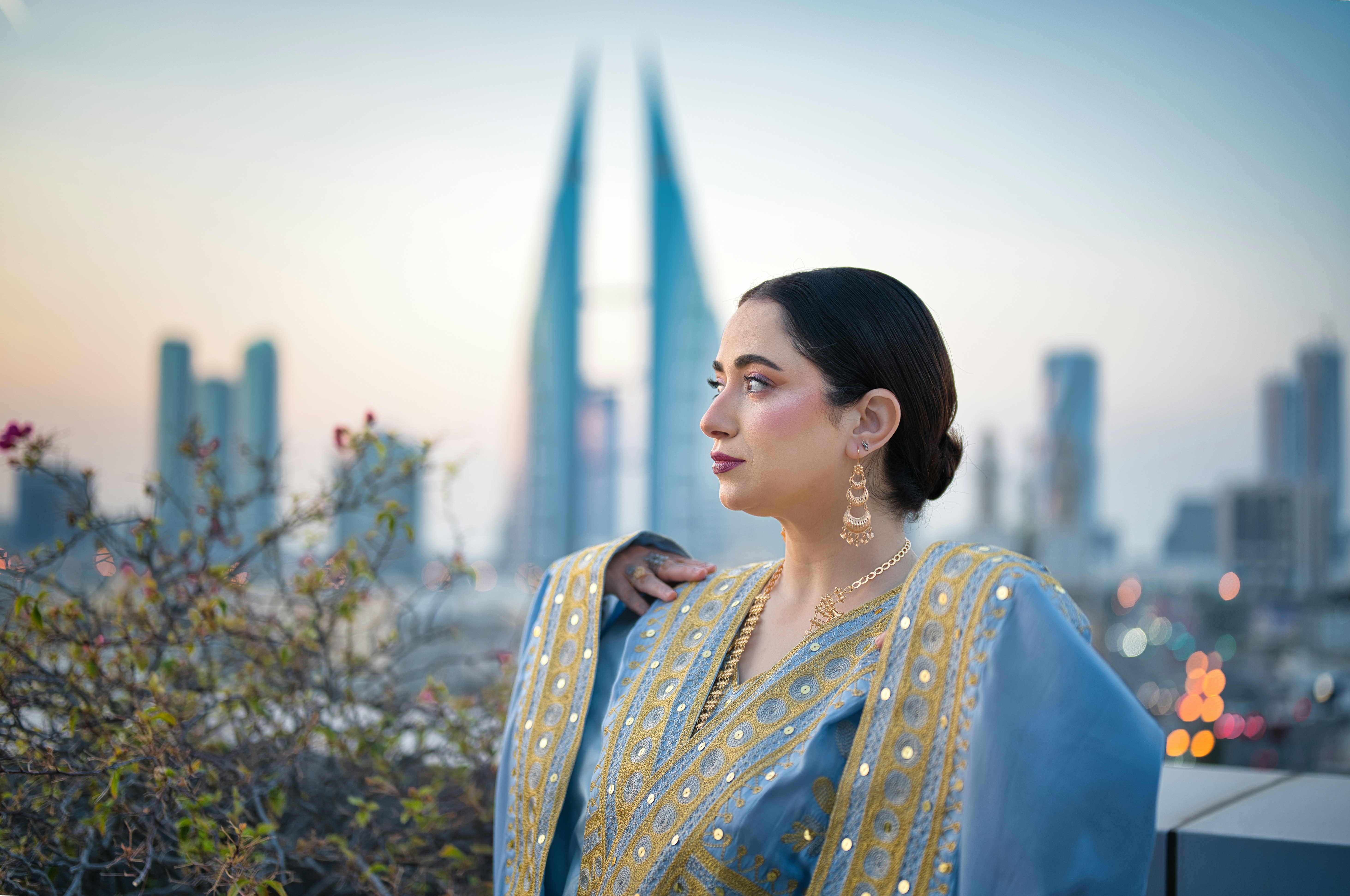 Portrait against a city silhouette: serene gaze with a traditional blue and gold drape
