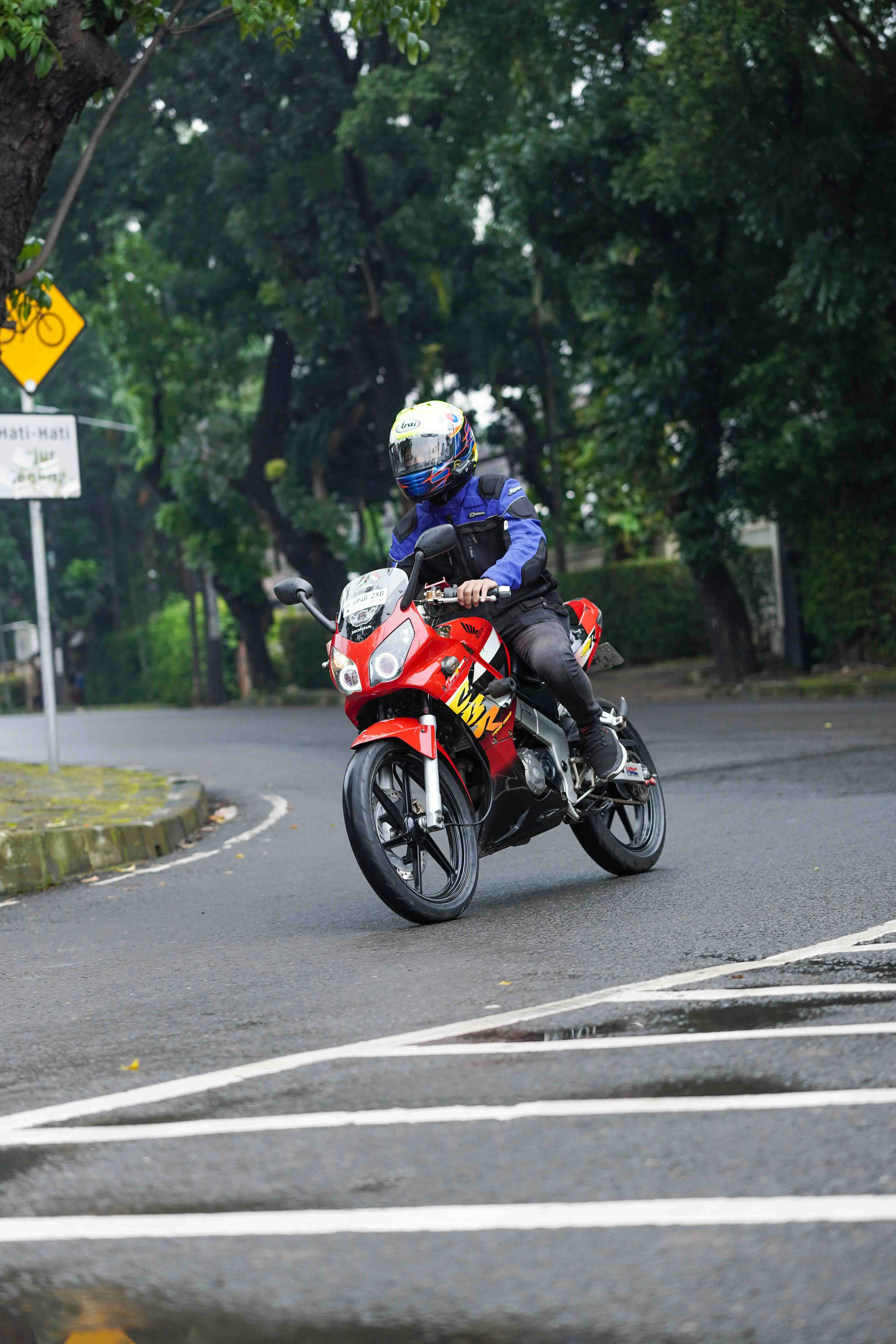 Rider in blue jacket carving the curve on a bold red motorcycle