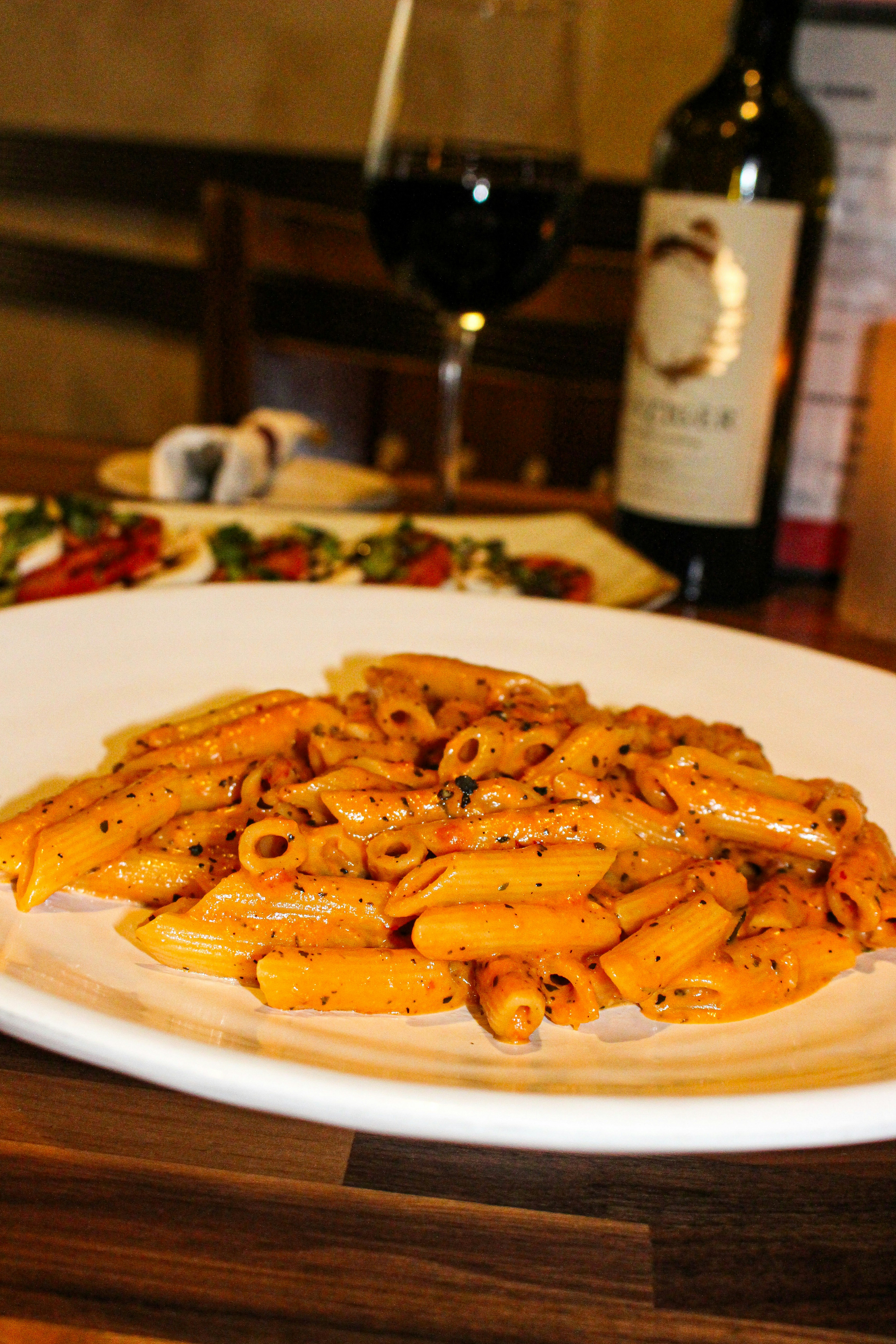 Plate of Penne in glossy sauce with wine and bakery background