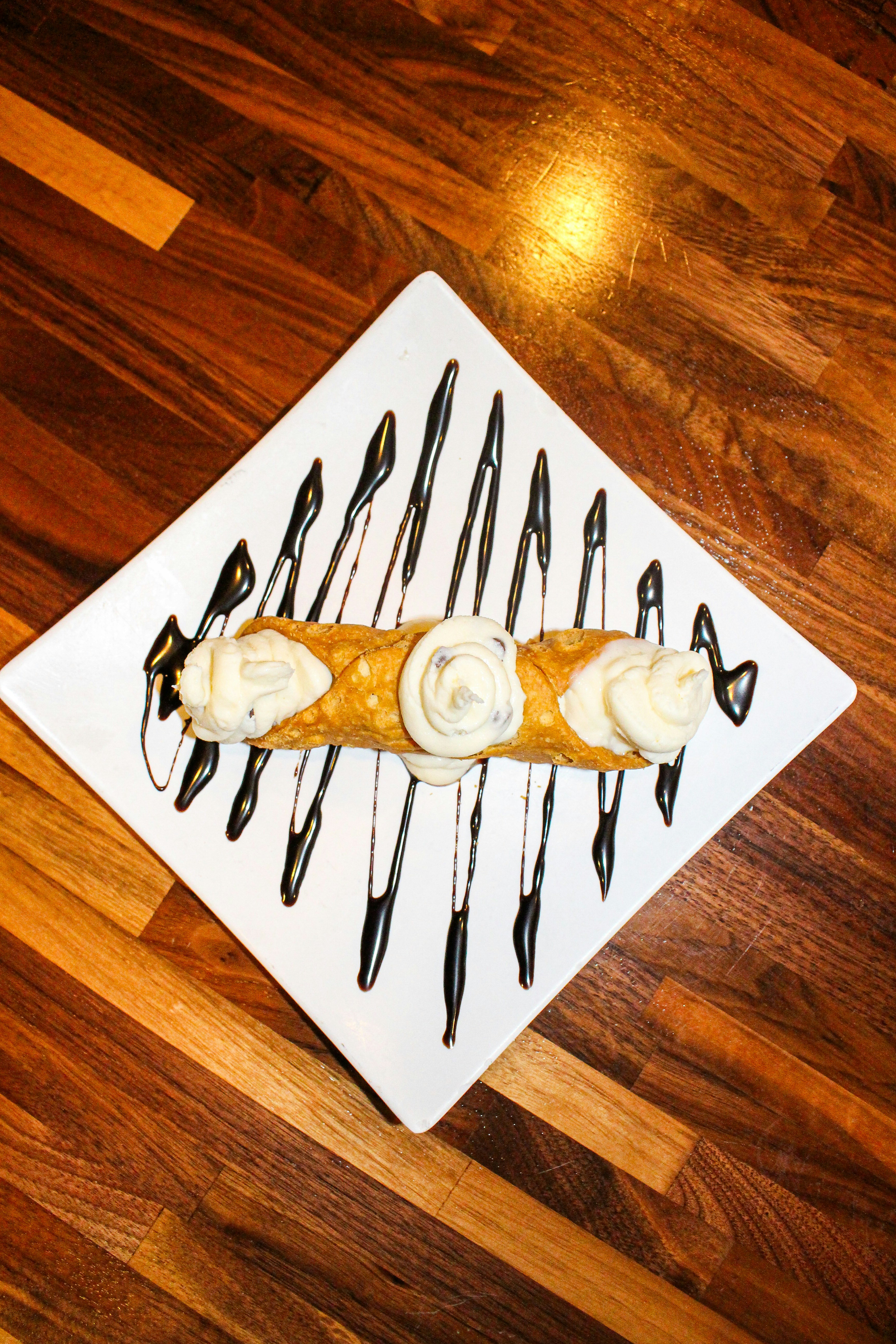 Citrus drizzle on a pastry crown: a plated dessert shot on a wood table