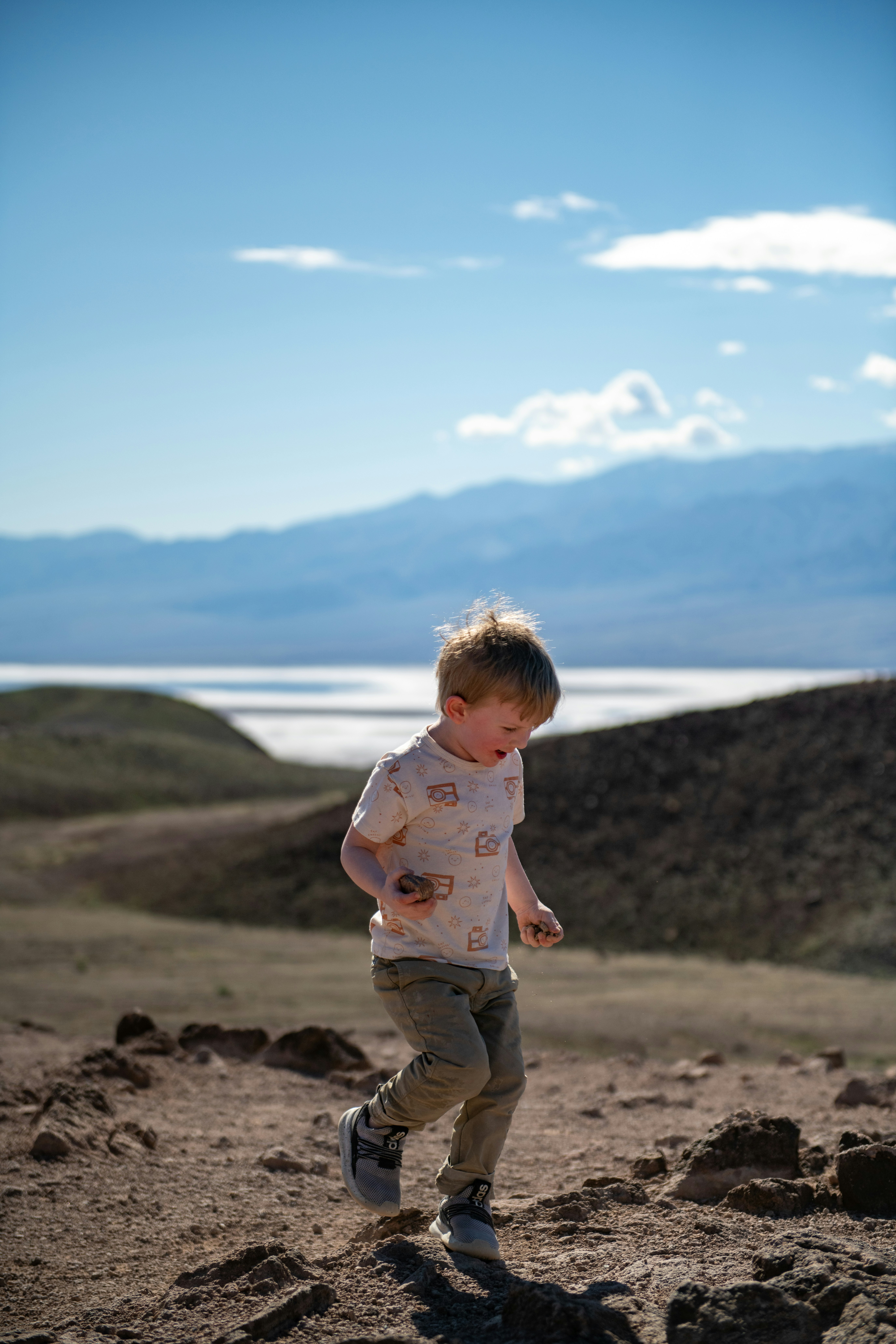 Child's Grounded Play Amid Deserted Shoreline and Distant Peaks