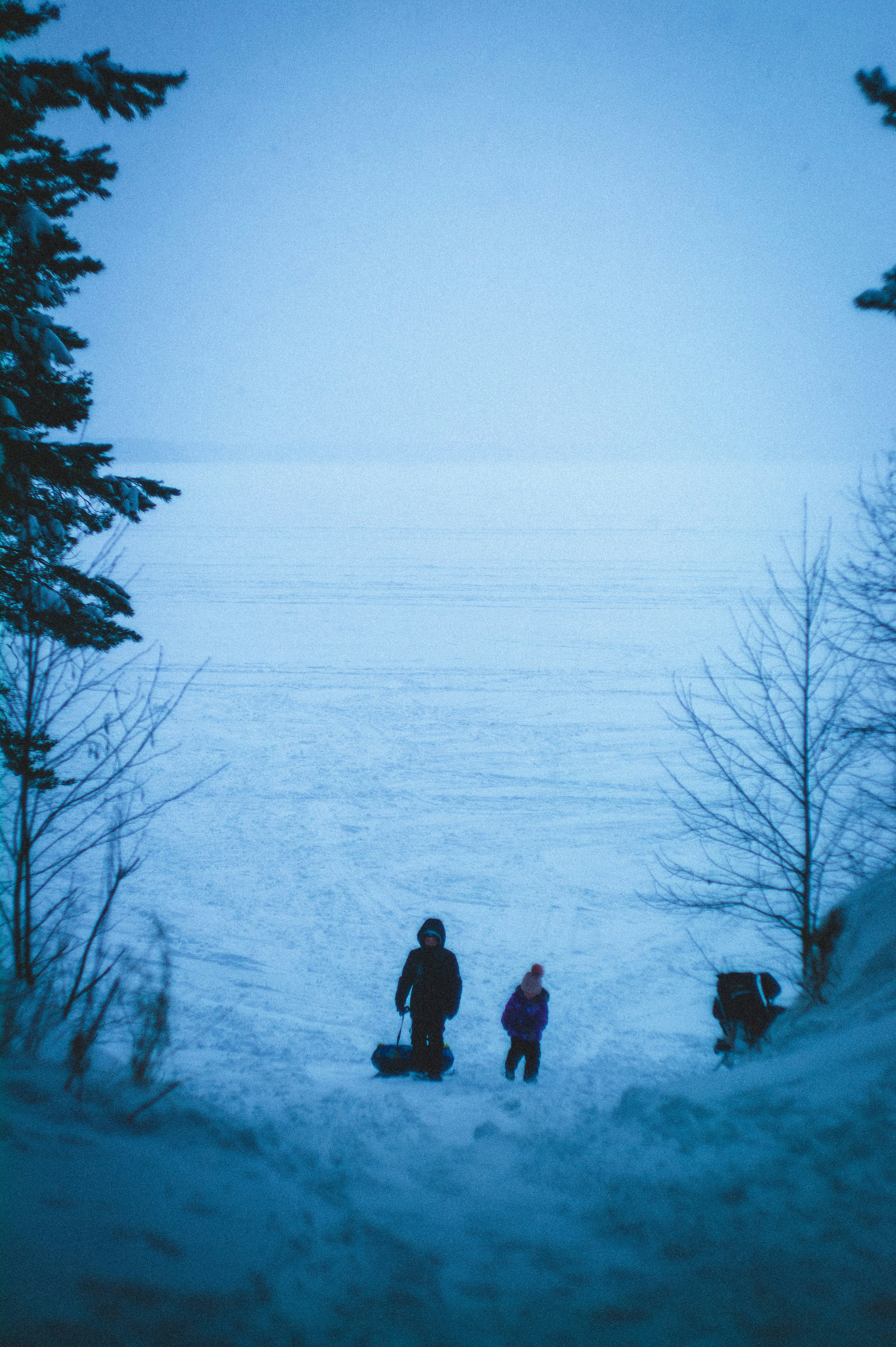 Two children with sleds on a snowy landscape