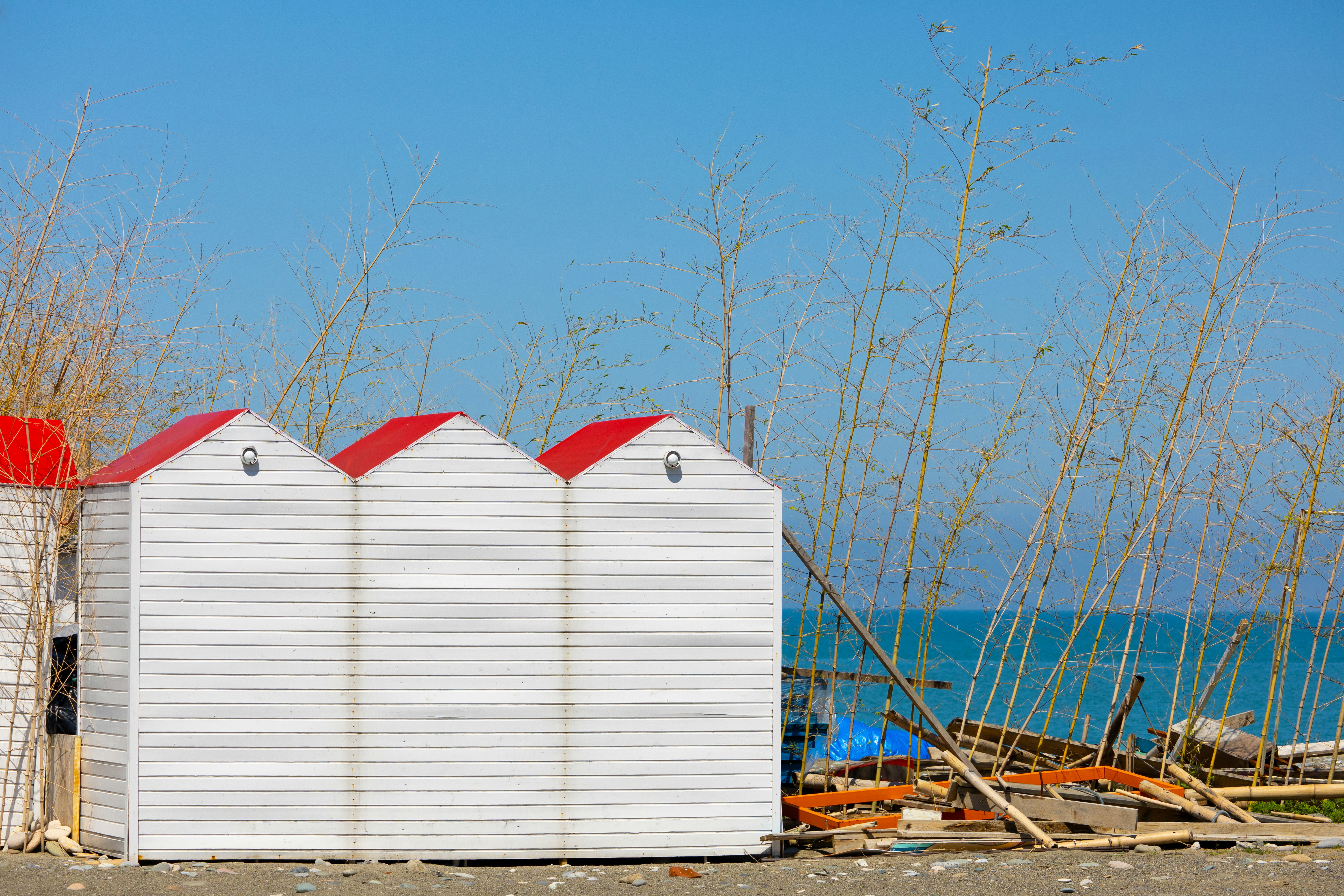 Row of white beach huts with red-roof accents by the shoreline