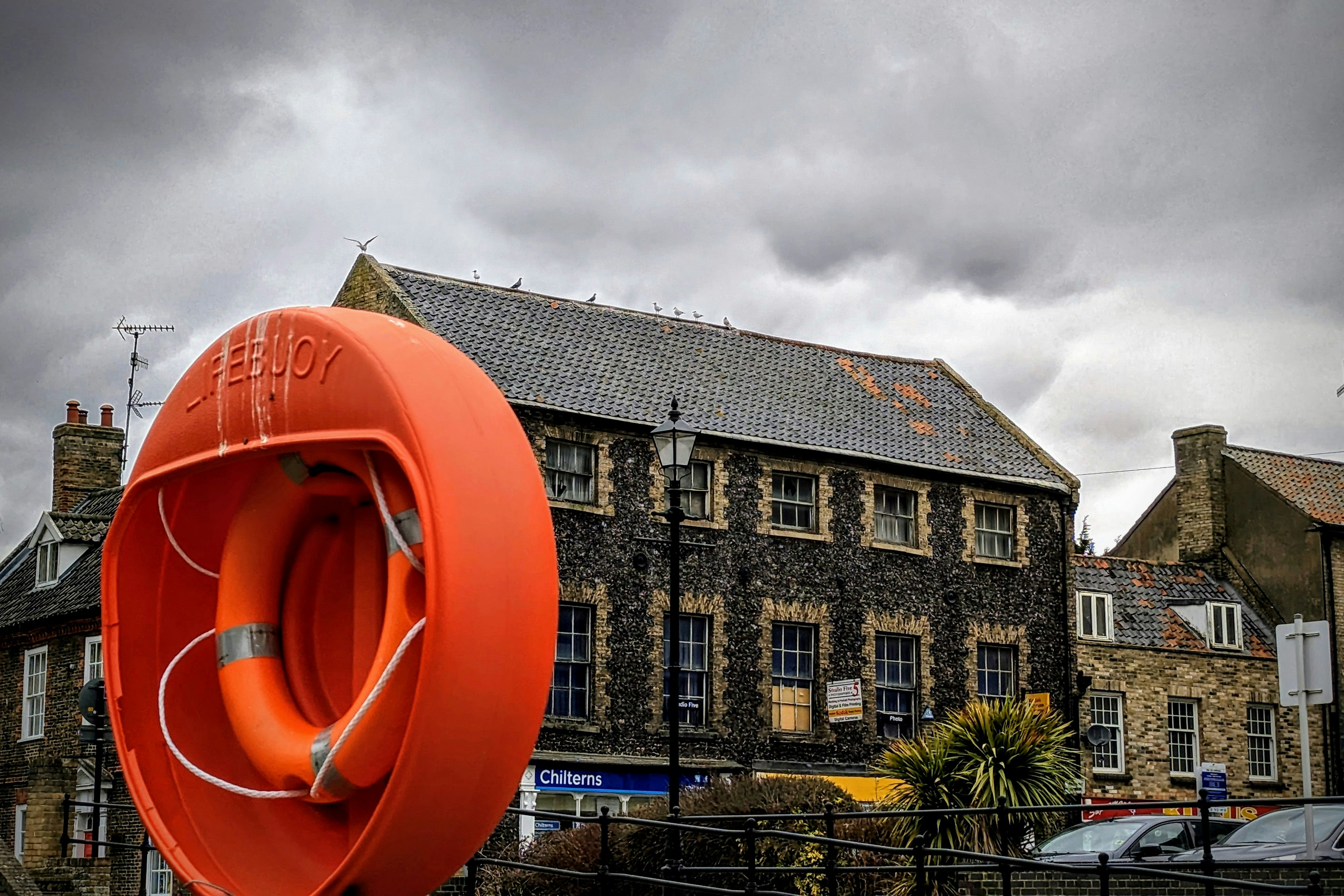 Lifesaver by the Quayside: A Bold Orange Ring Overlooks a Stone Street
