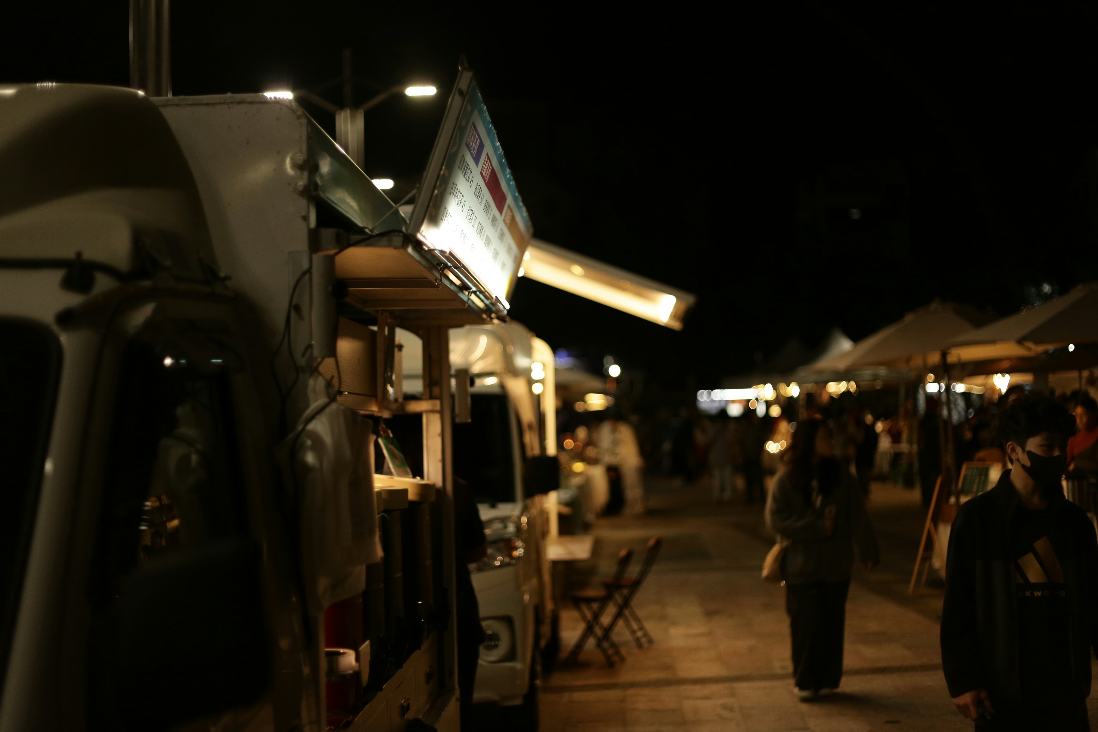 Night Market Glow: A Food Truck Behind the Dusky Crowd