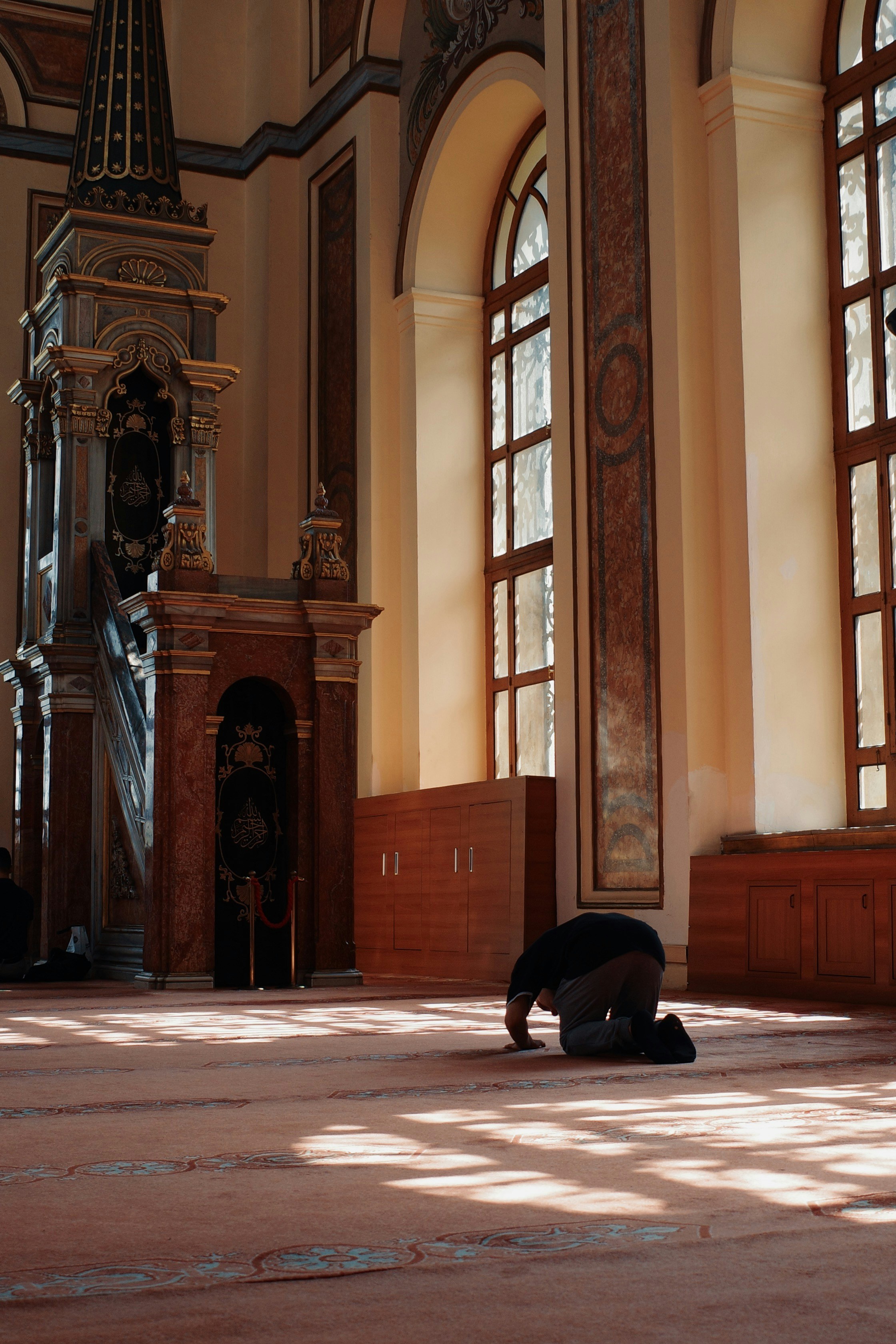 Kneeling Figure in a Sunlit Sacred Hall