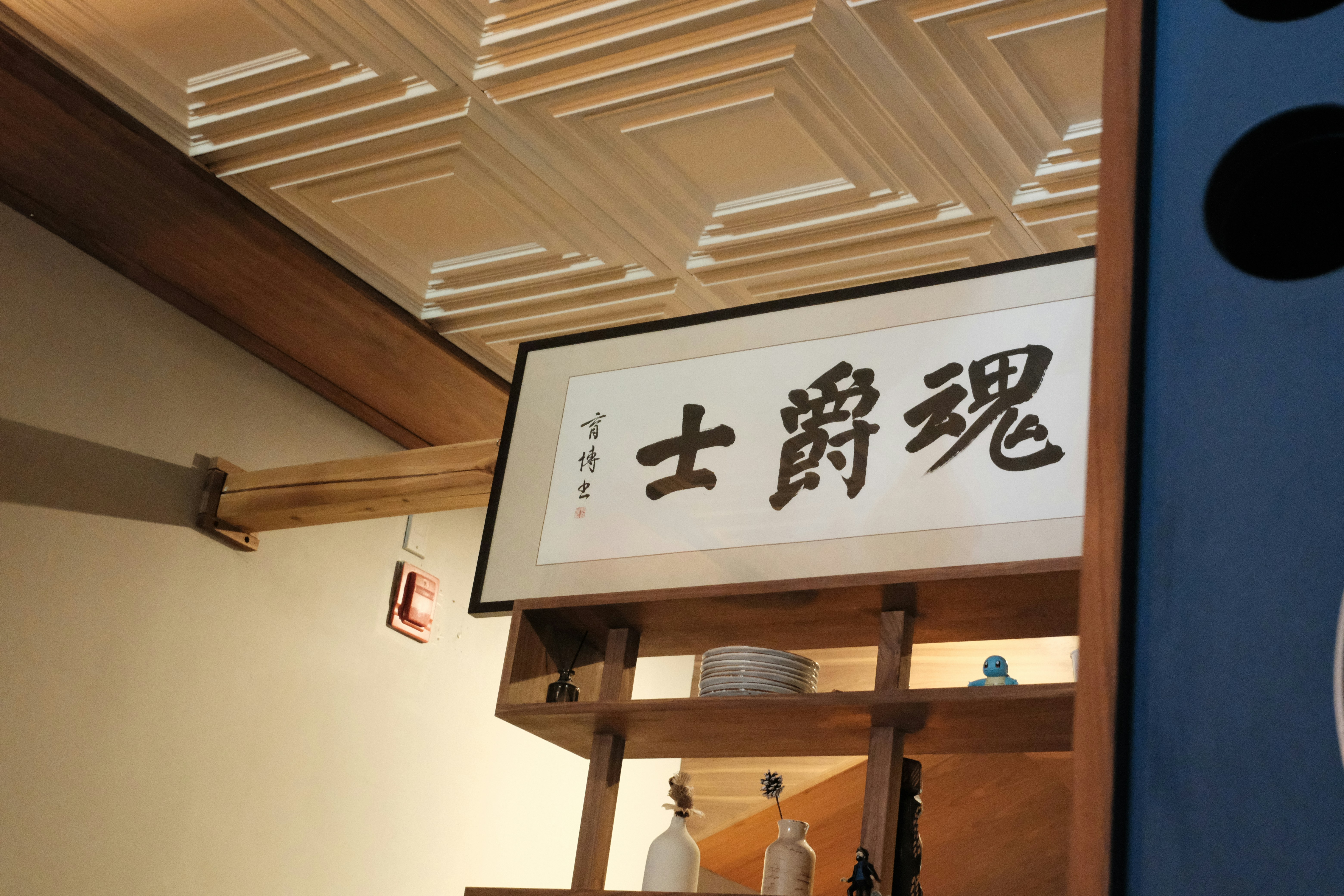Calligraphy Frame Above a Wooden Display in a Cozy Interior