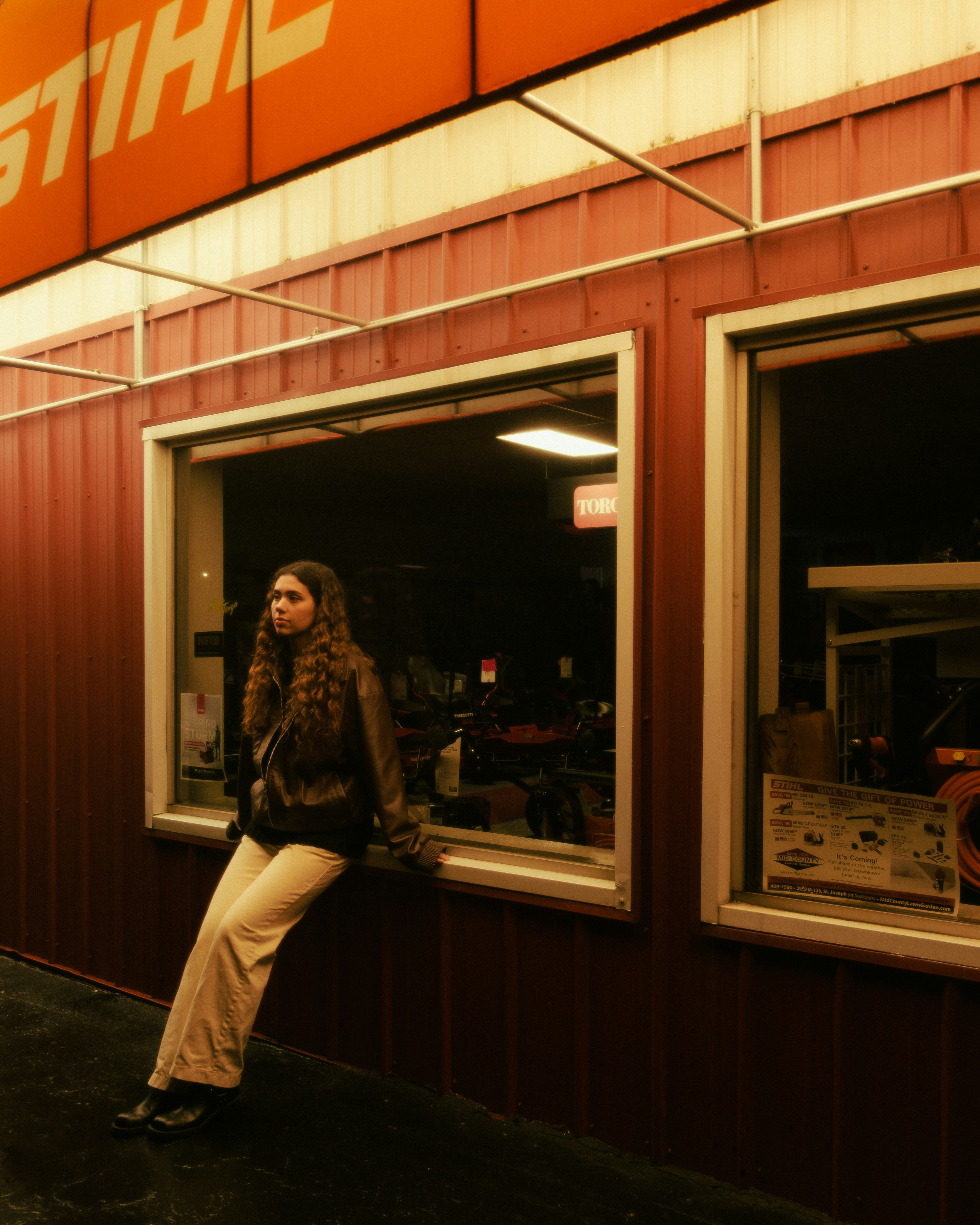 Against the Red Wall: A Quiet Moment by the Shop Window
