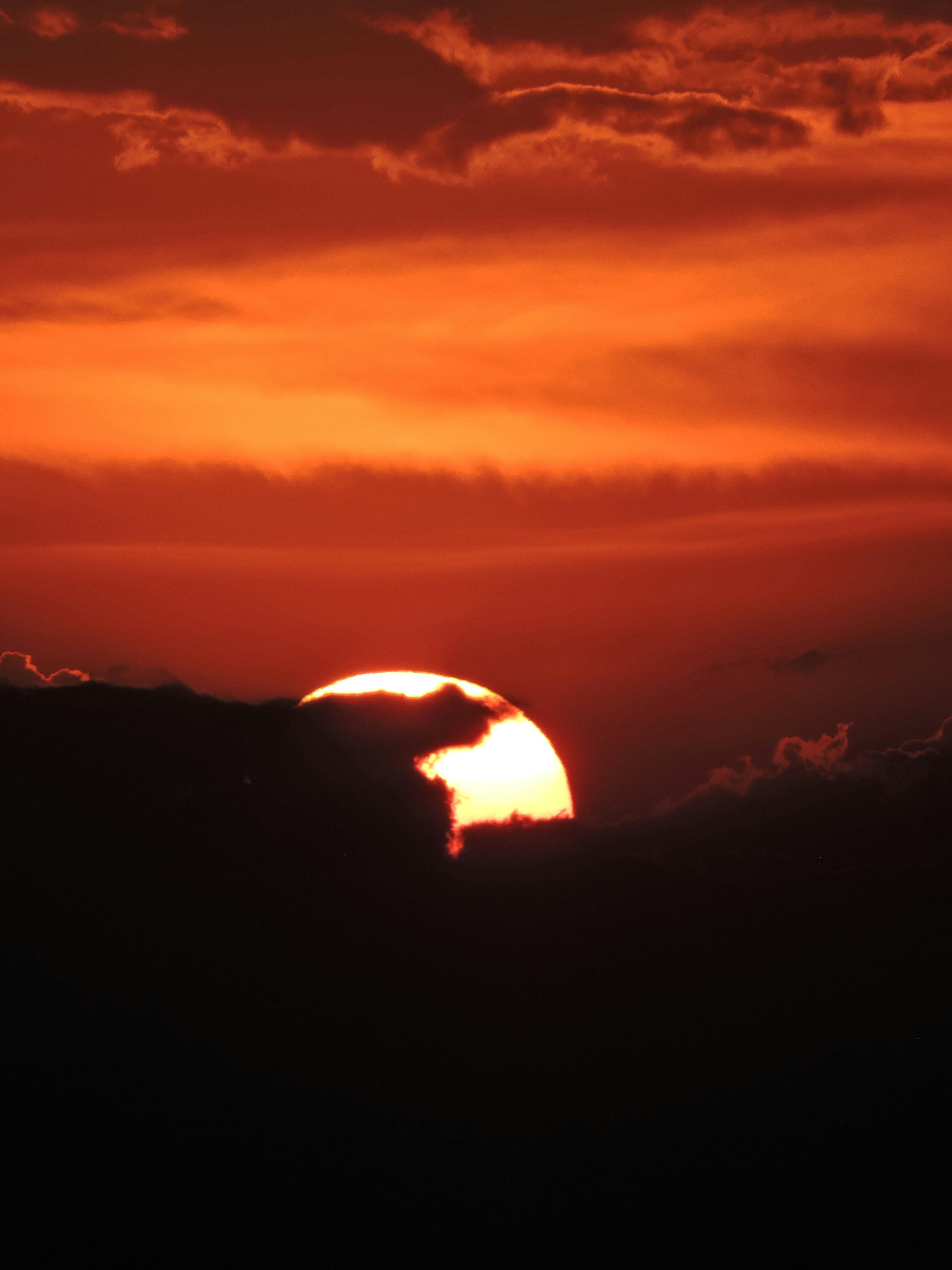 Fiery sunset with dramatic clouds and glowing sun.