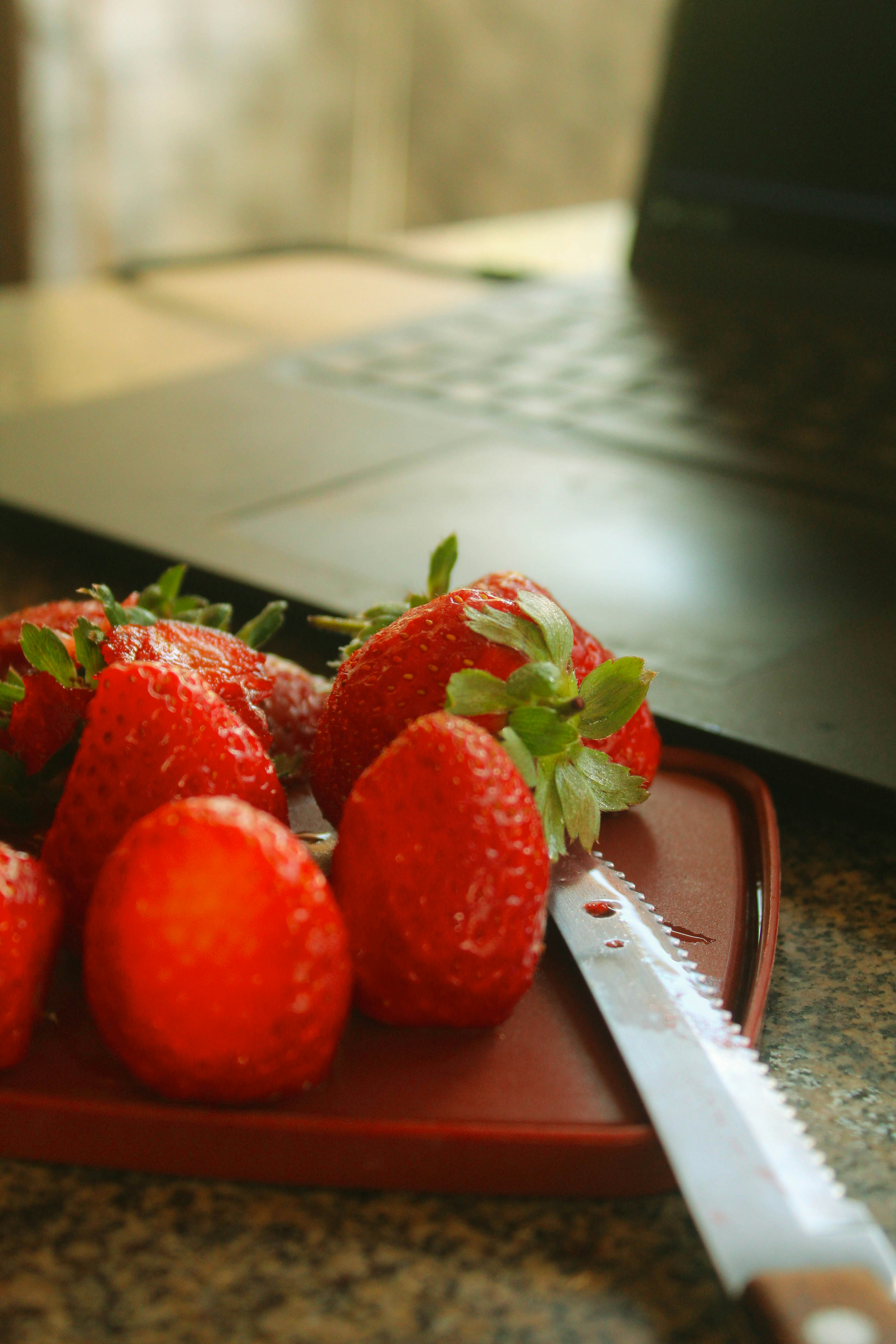 Red berries on a kitchen platter with a knife beside them