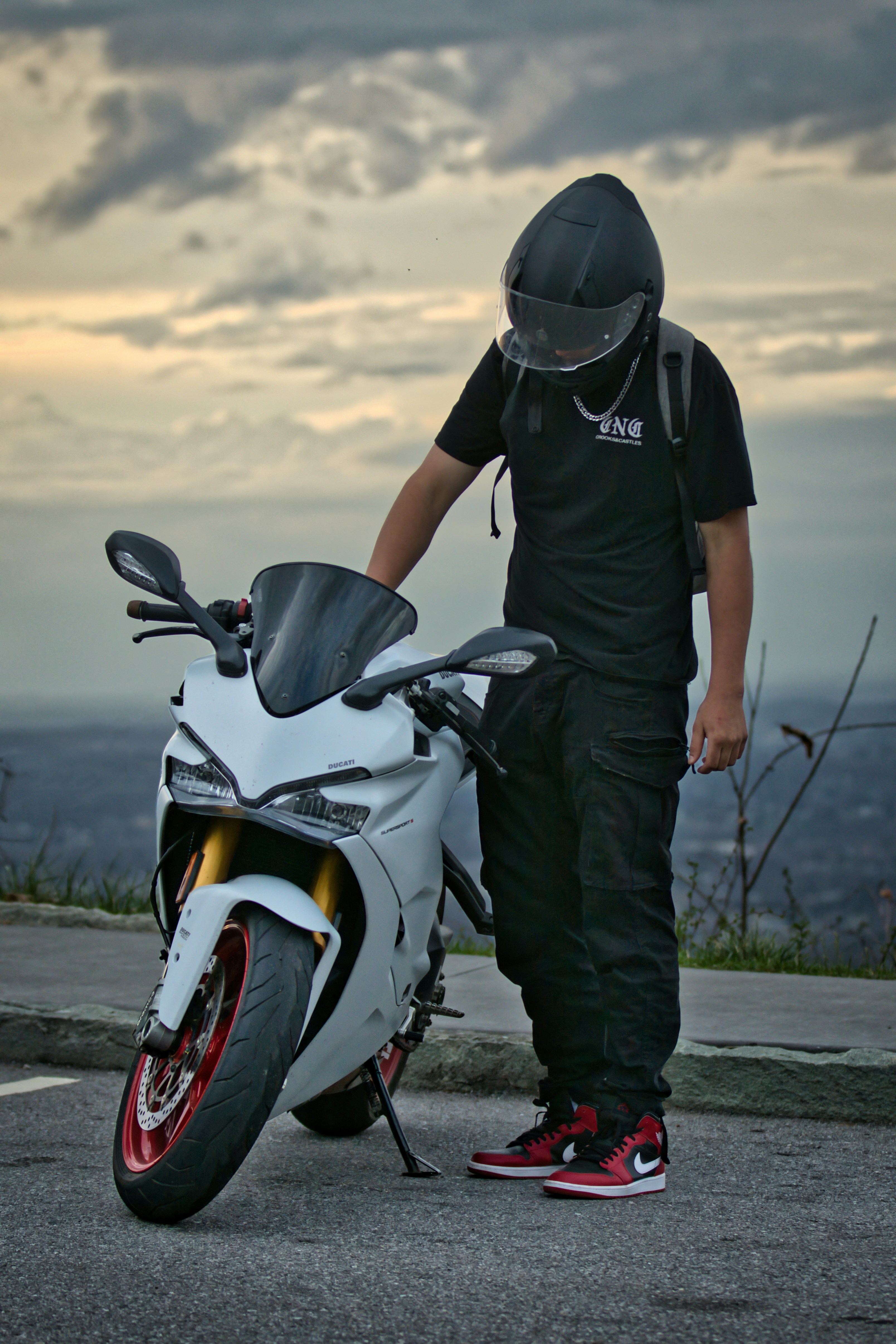 Person in helmet stands by white motorcycle