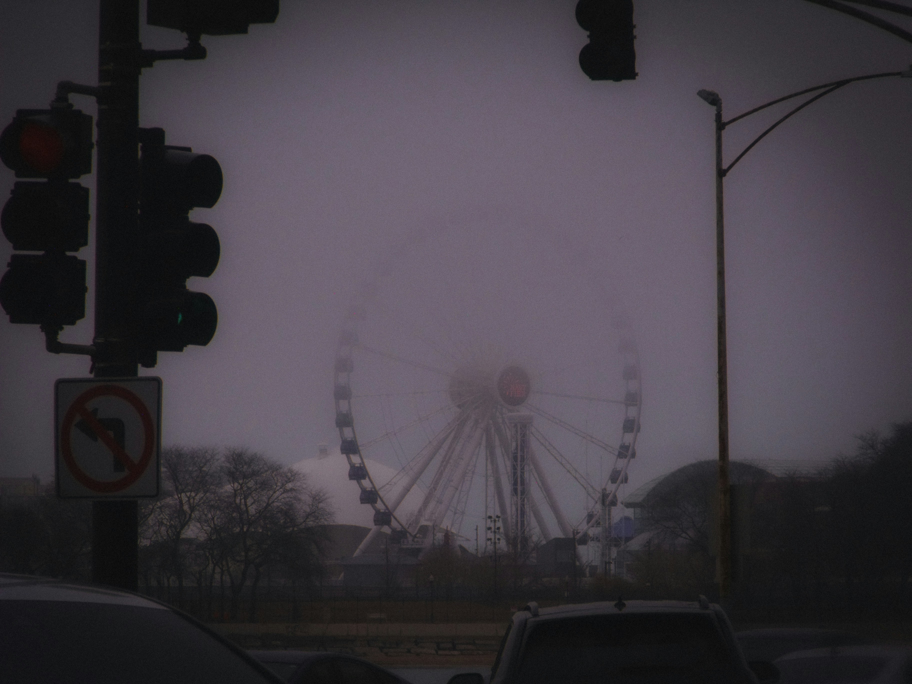Ferris wheel obscured by thick fog on a gloomy day.