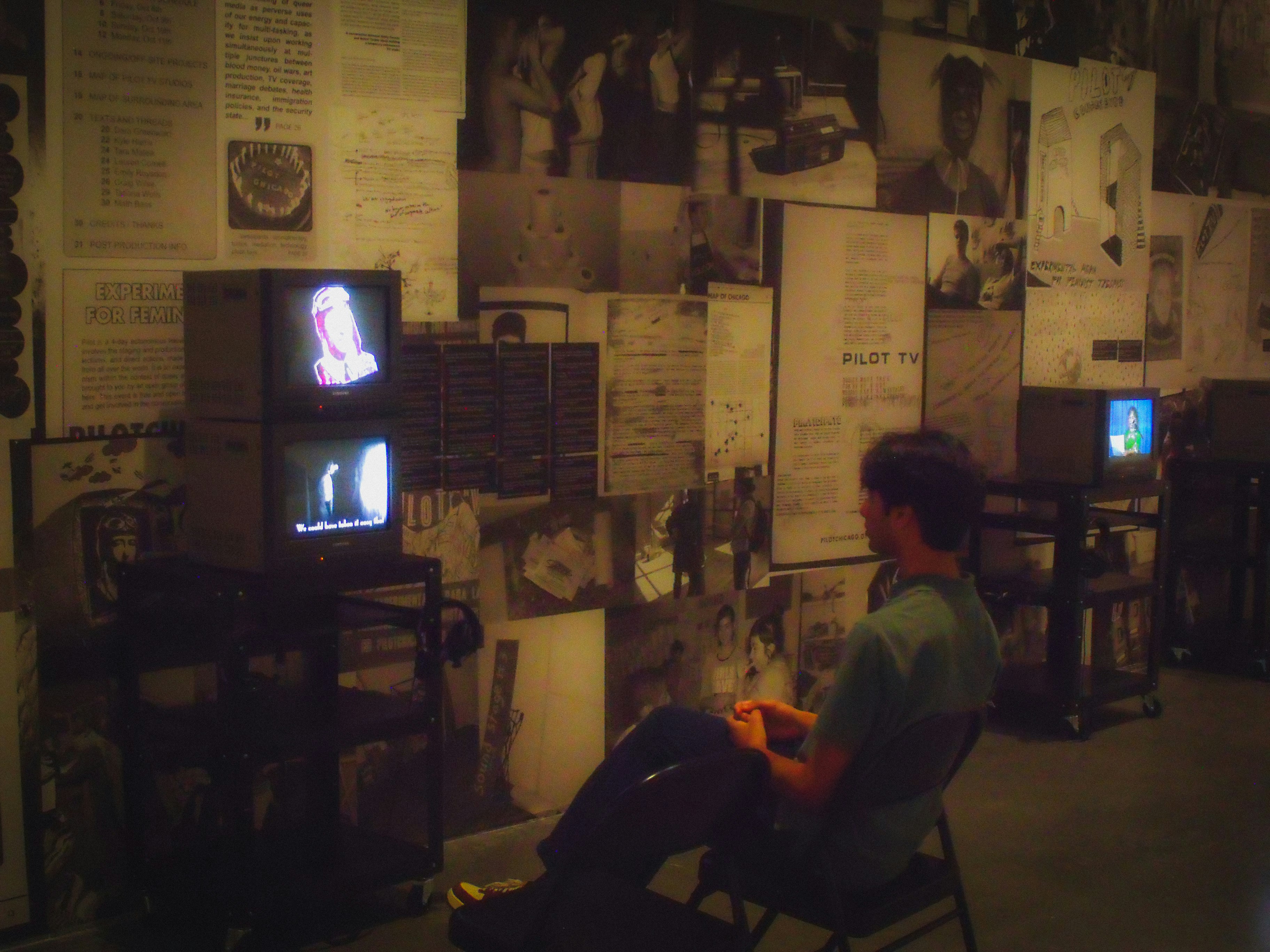 Person watching multiple screens with posters on wall