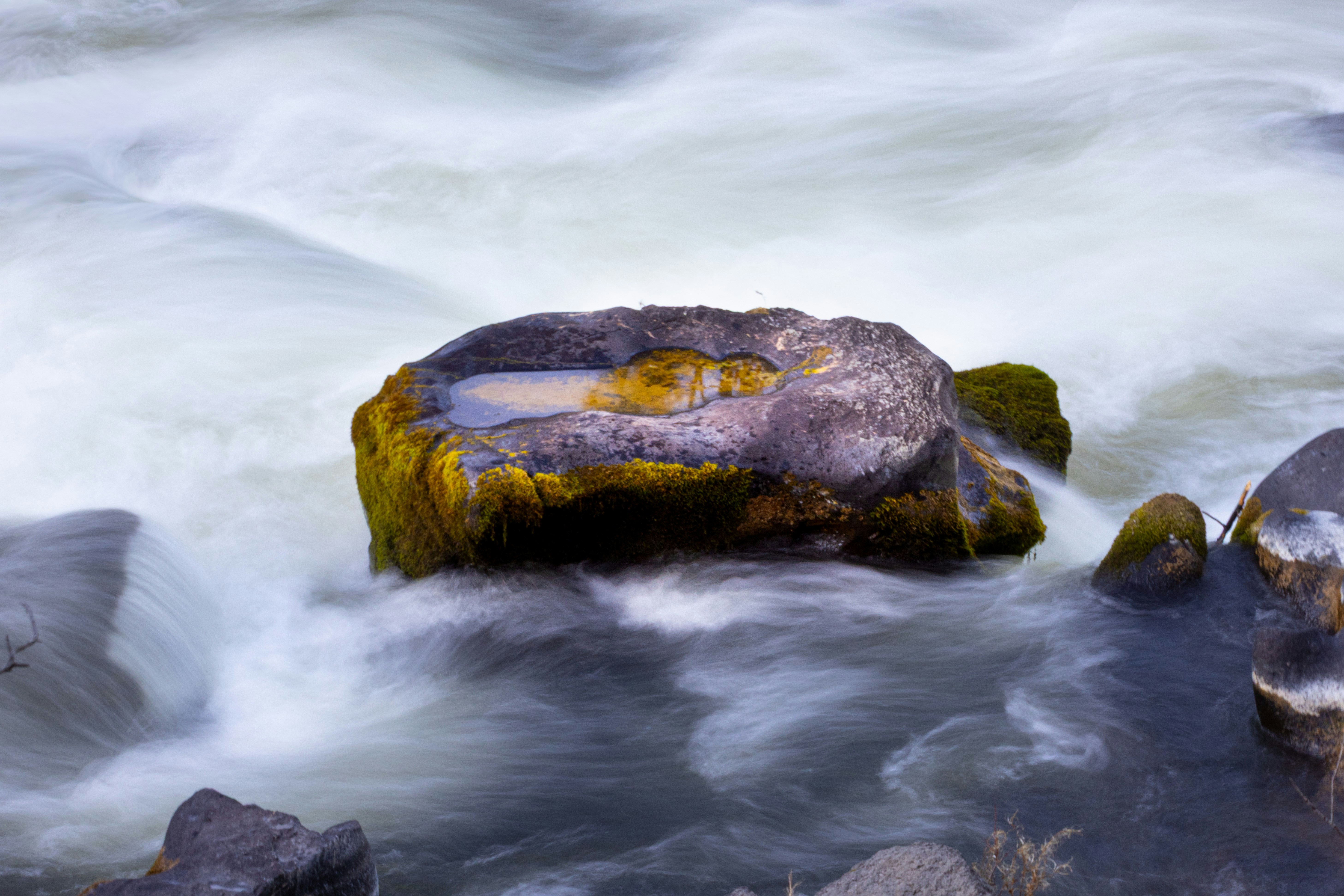 A lone rock cradle amid a milky tide