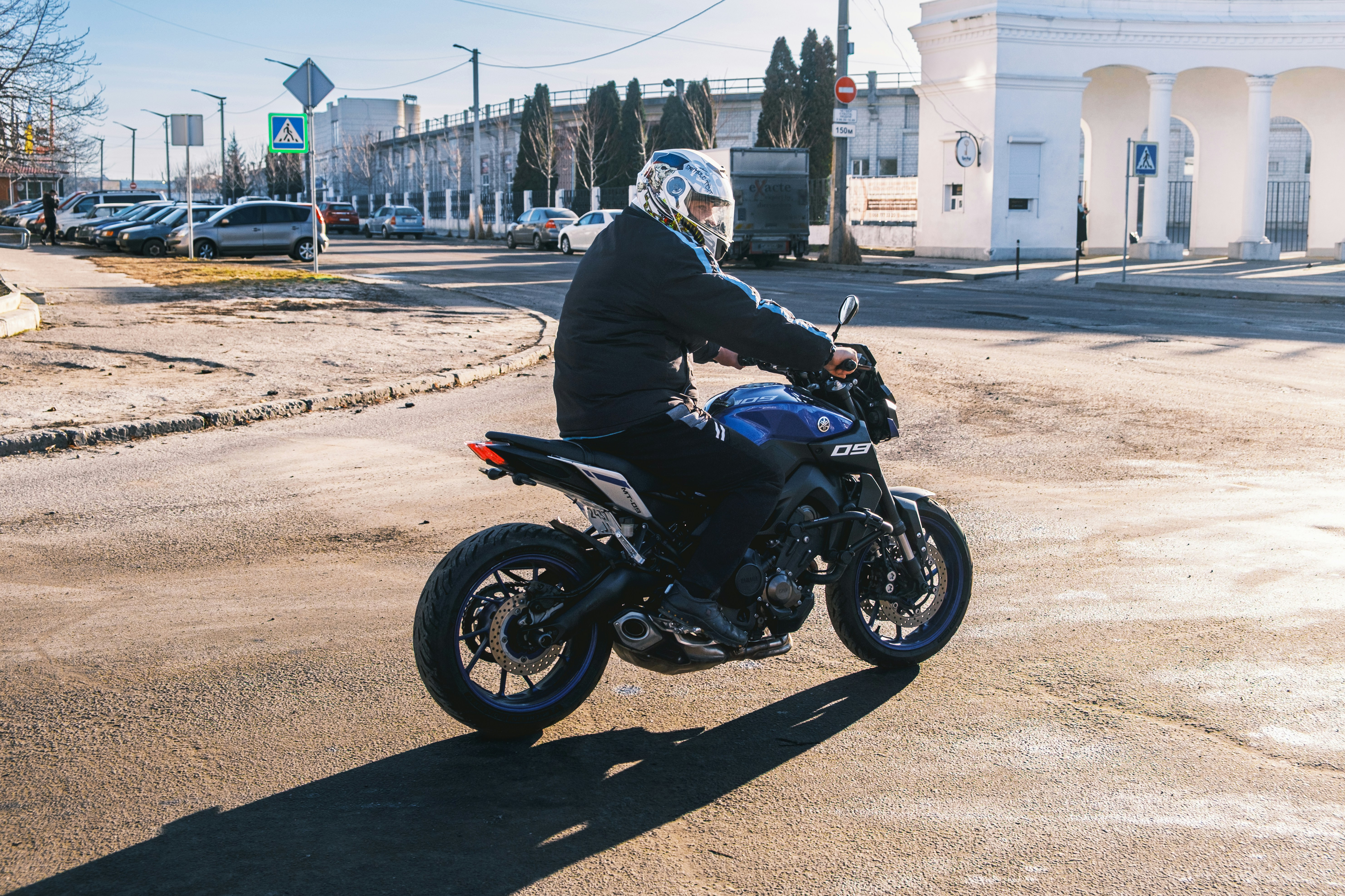 Mid‑Street Rider: A Blue Motorcycle Pauses at an Urban Crossing