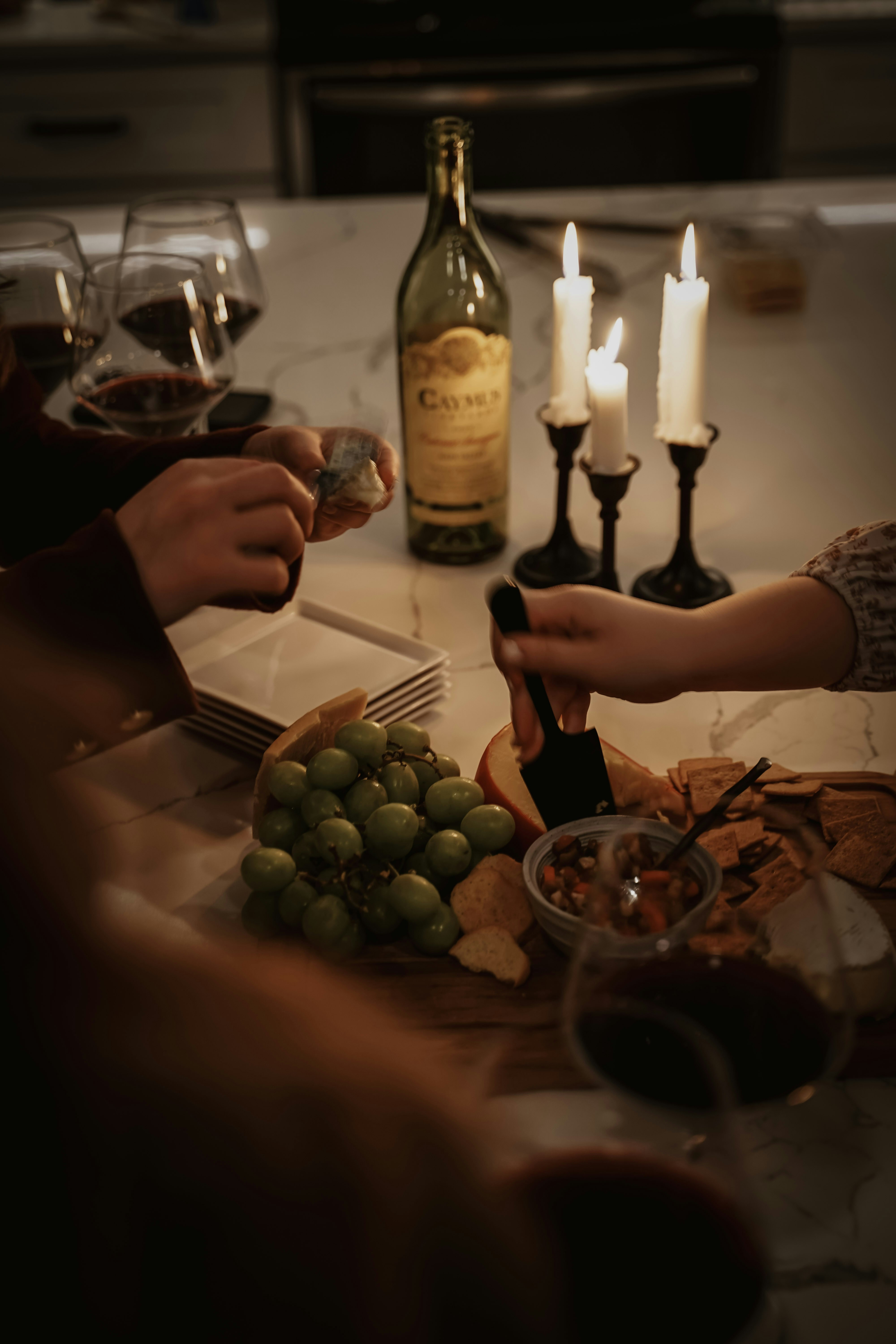 Candlelit Feast: Grapes, Cheese, and Glasses in Warm Evening Glow