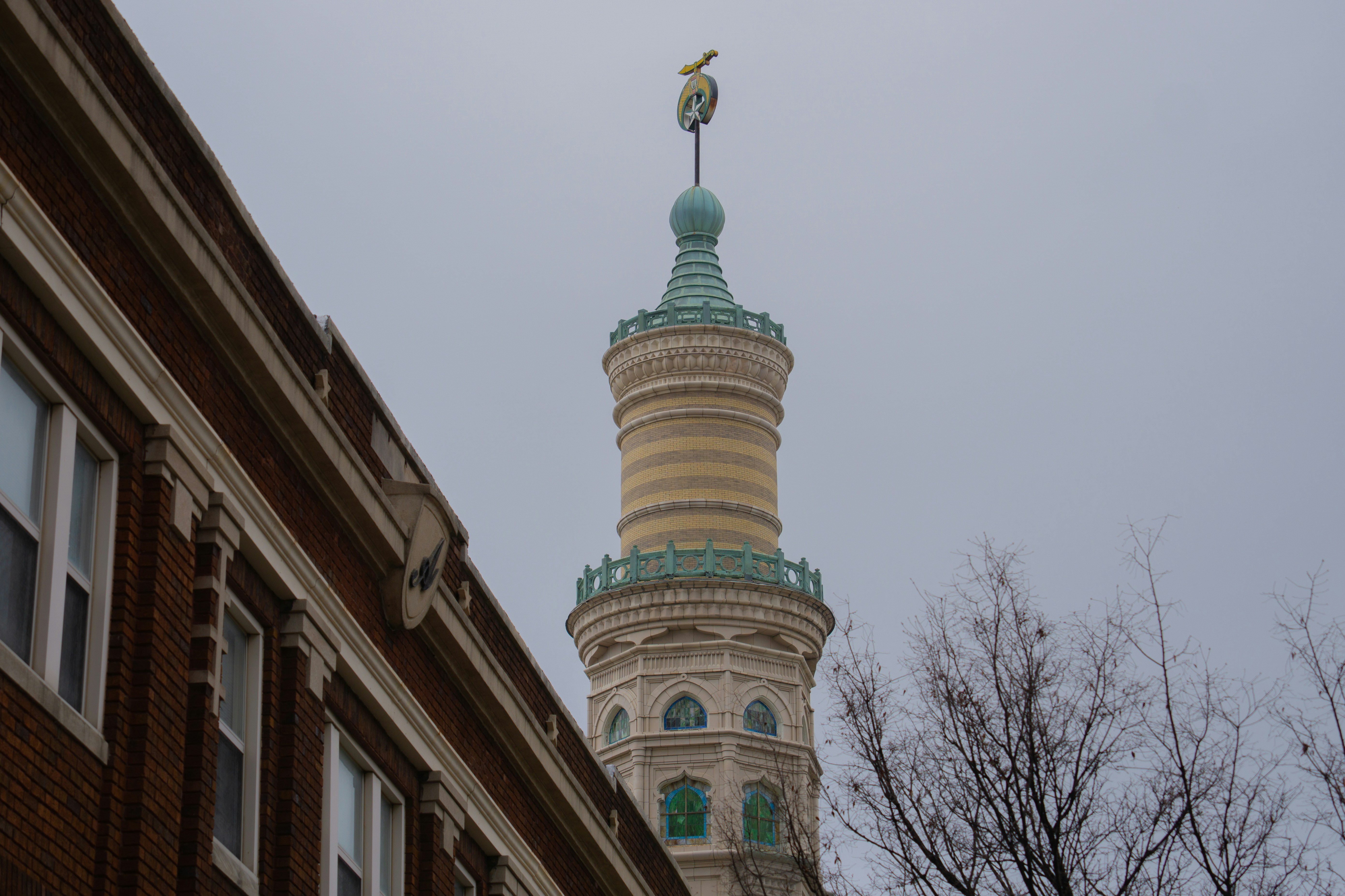 Towering Ornament: The Green-Topped Spire Rising Over Brick Facades