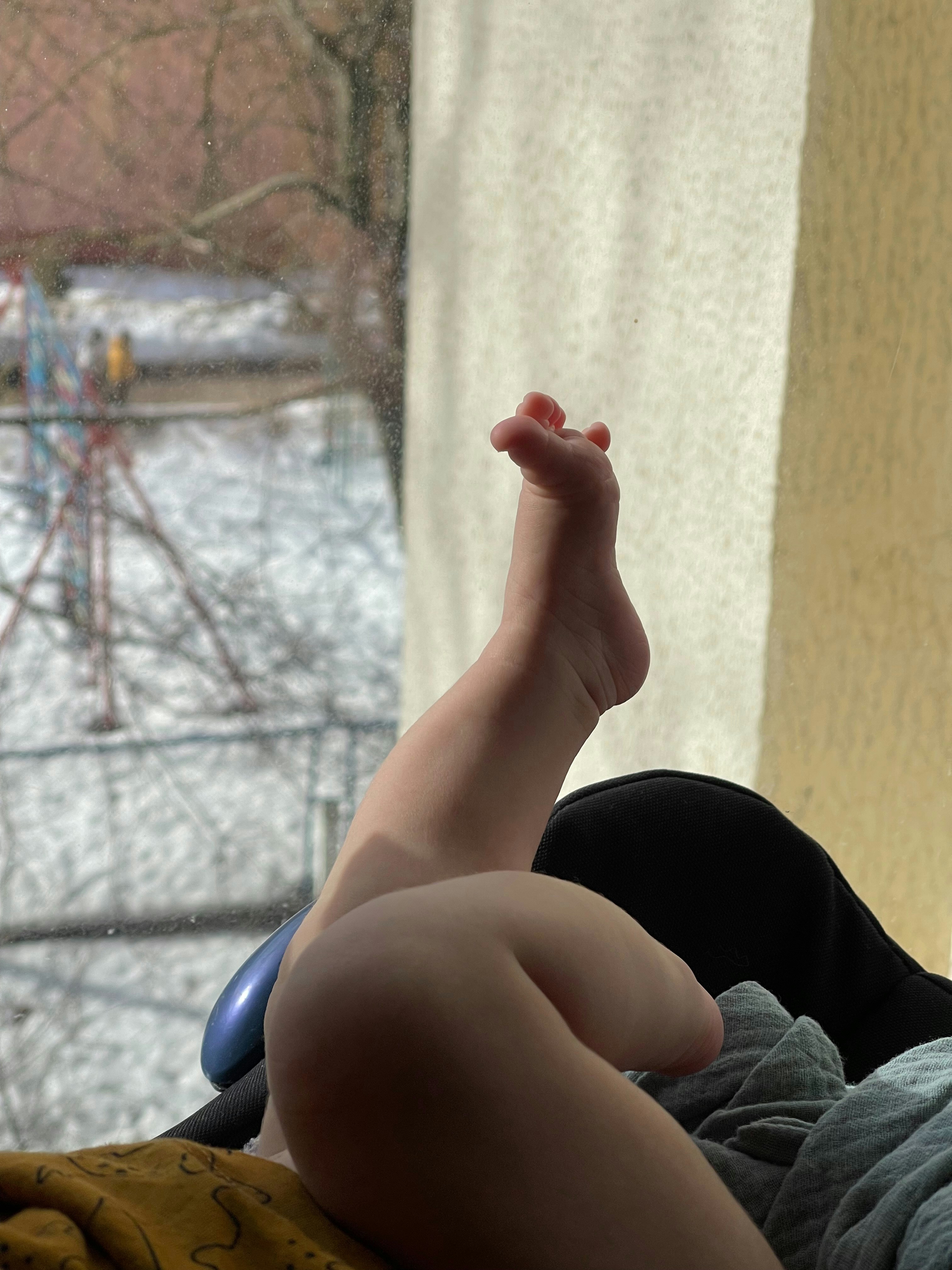 Tiny Foot in Focus: A Baby’s Leg Resting by a Window