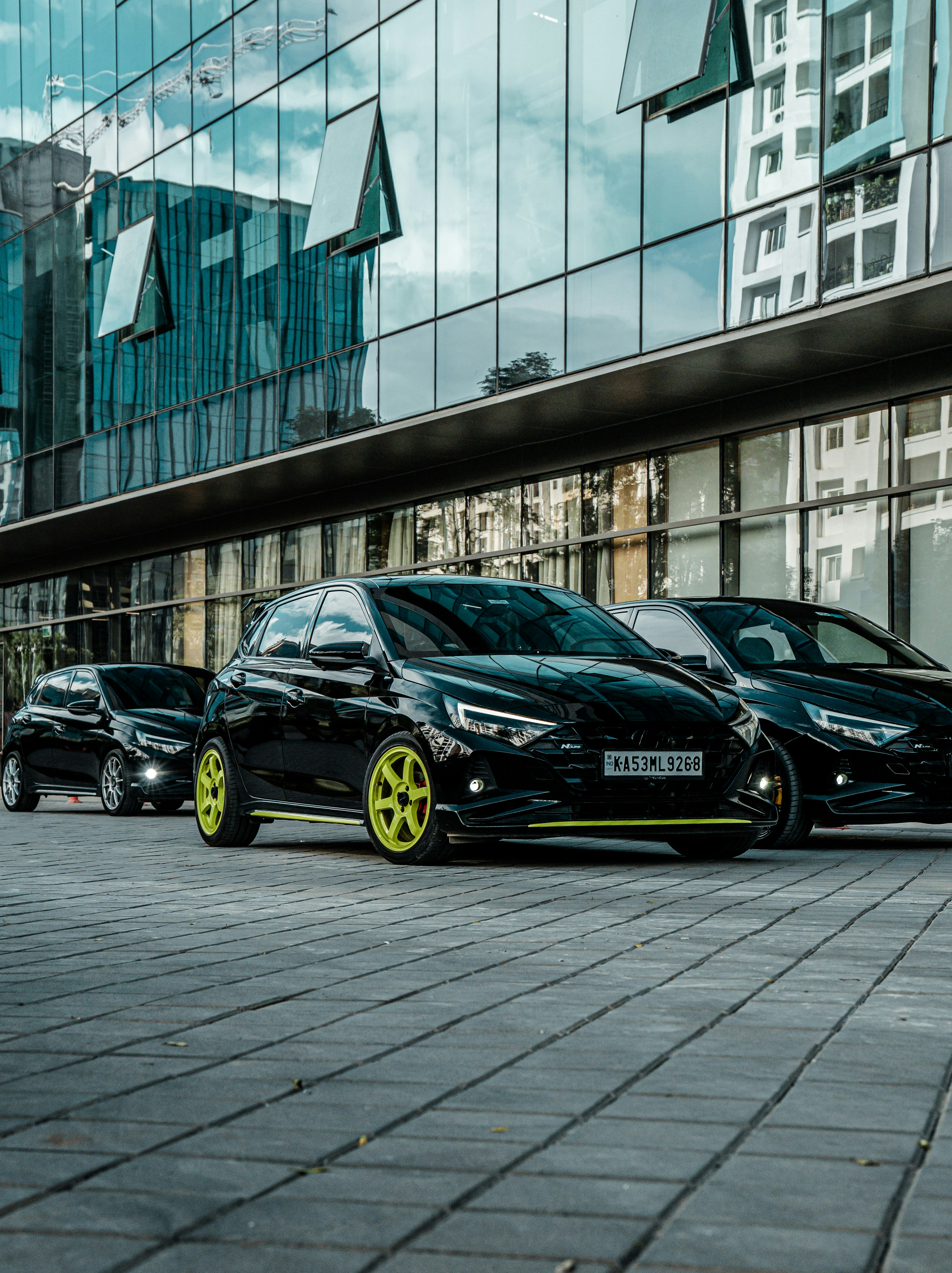 Neon-rimmed stance: a black hatchback with lime-green wheels anchors a modern urban lineup