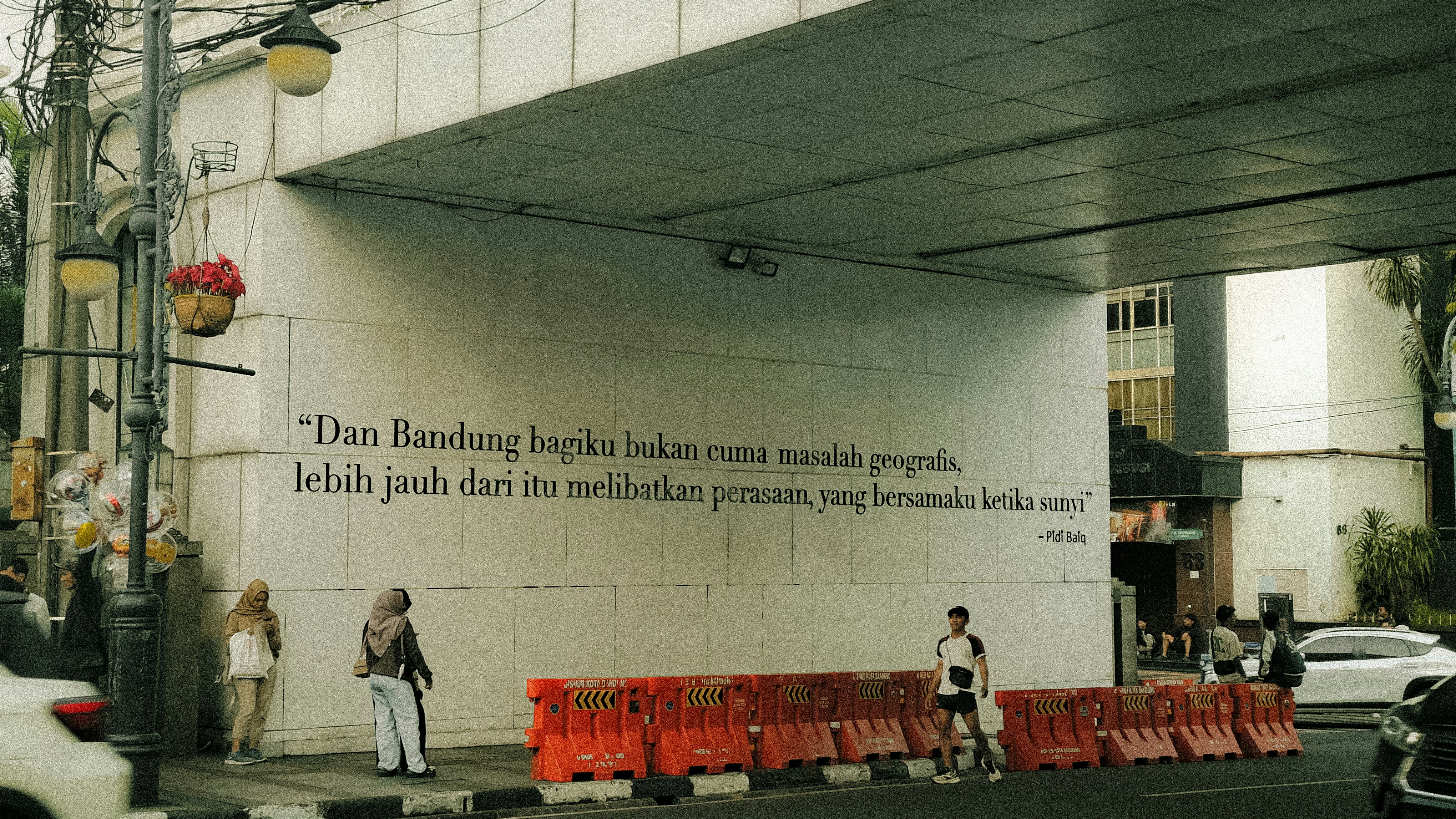 People walk past a mural with text on a building