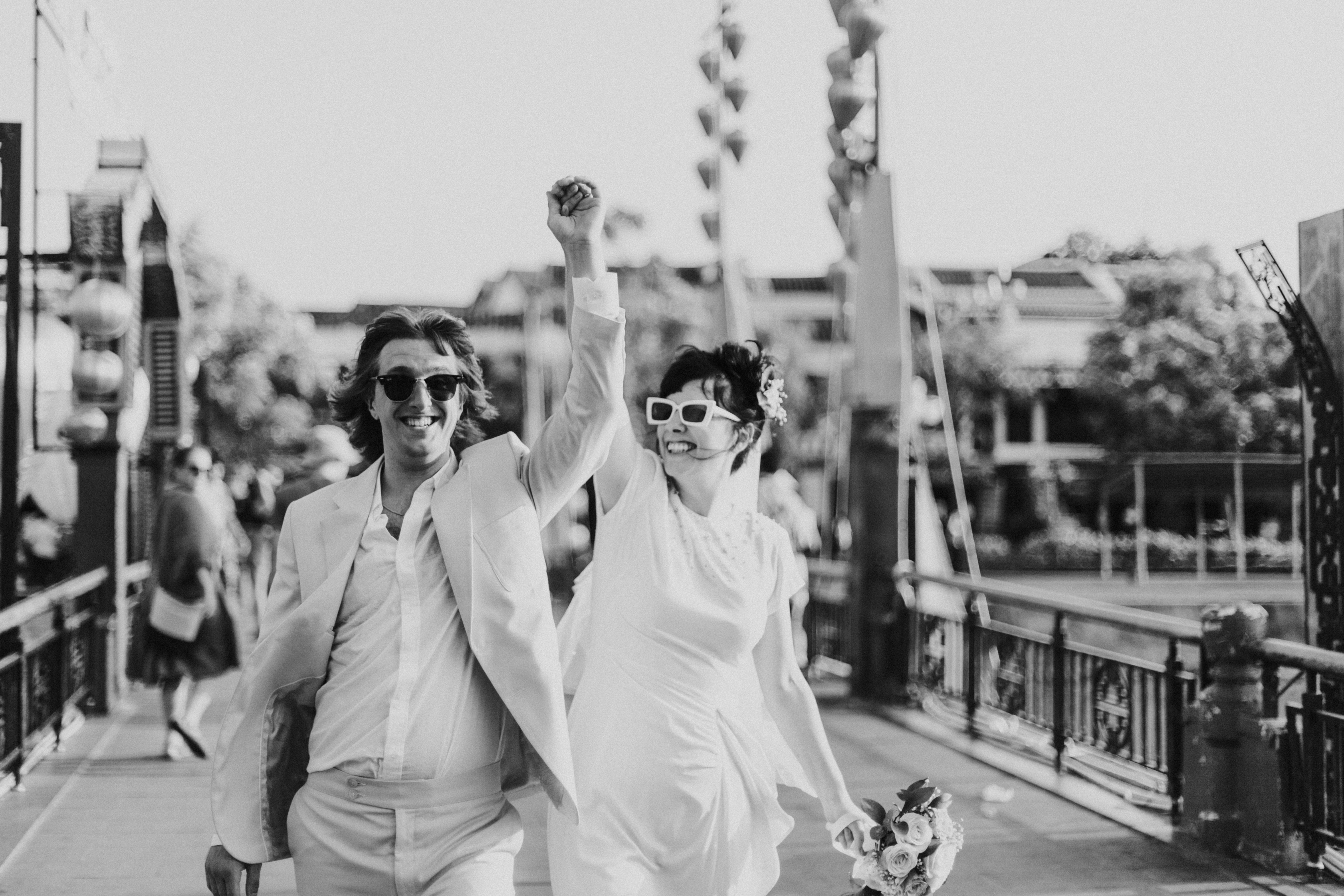 Joyful Rooftop Stroll: A Bride and Groom Raise Their Hands in Celebration