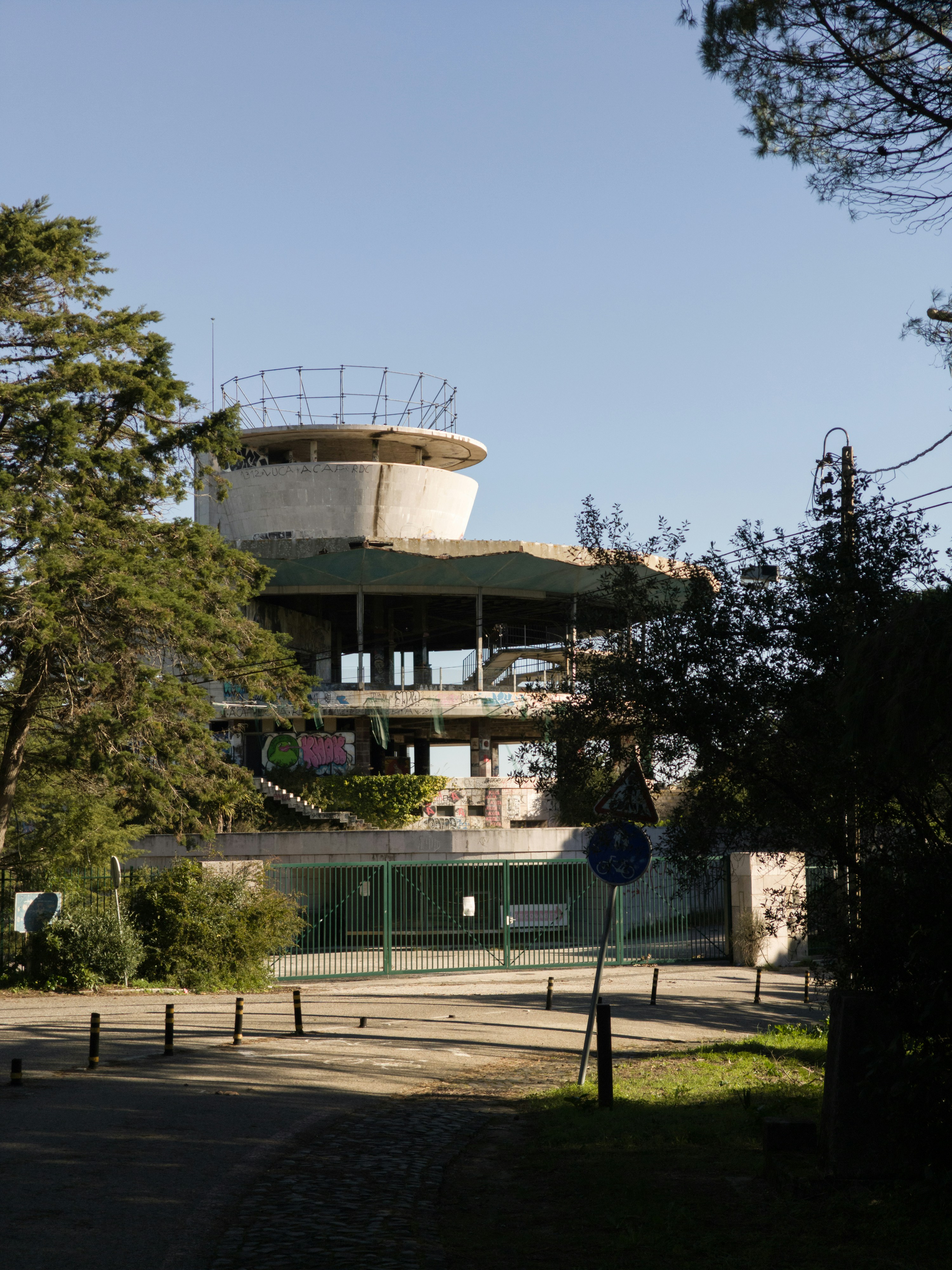 Abandoned building with graffiti surrounded by trees.