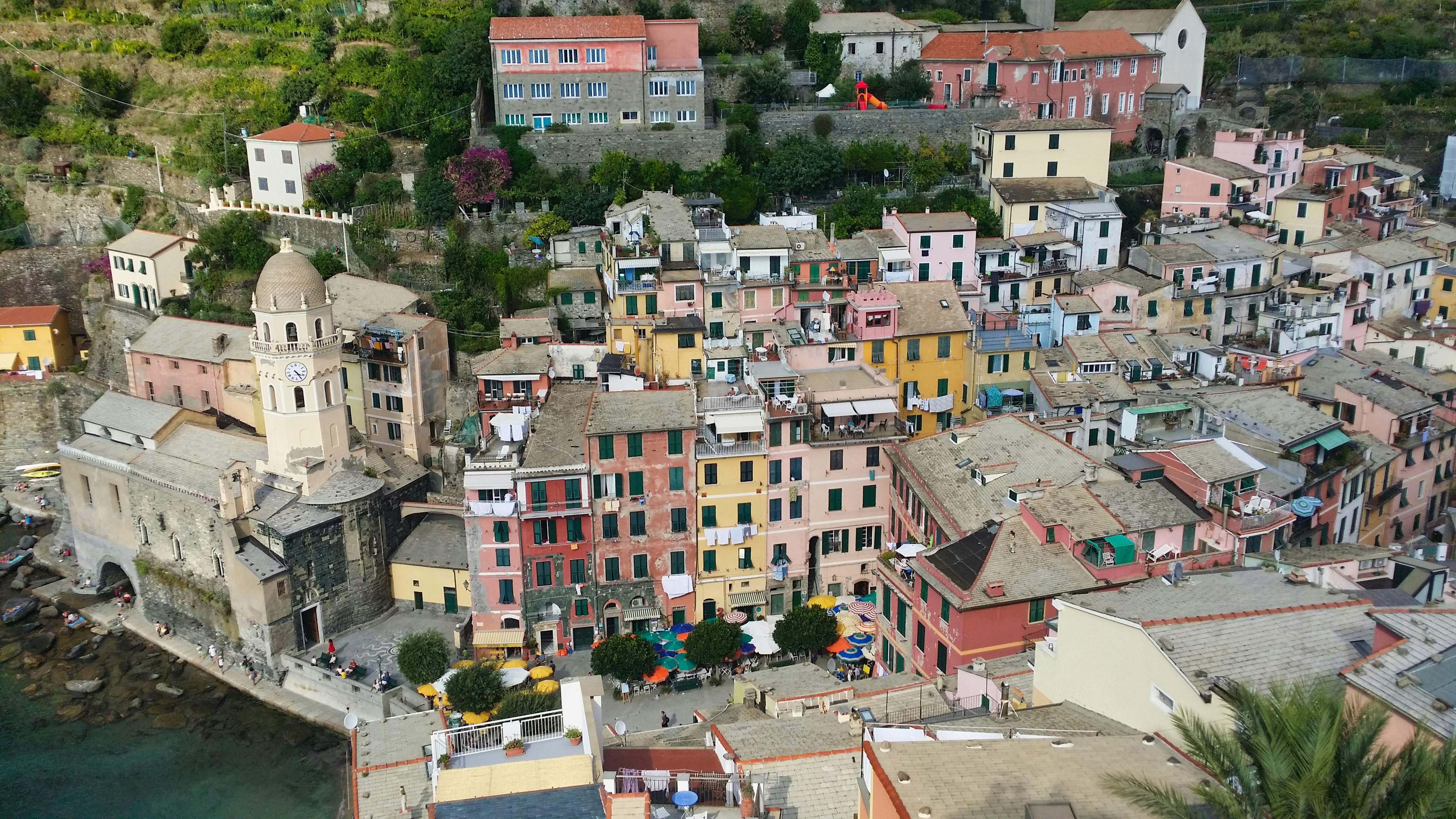 Colorful buildings line a coastal italian village with a church.