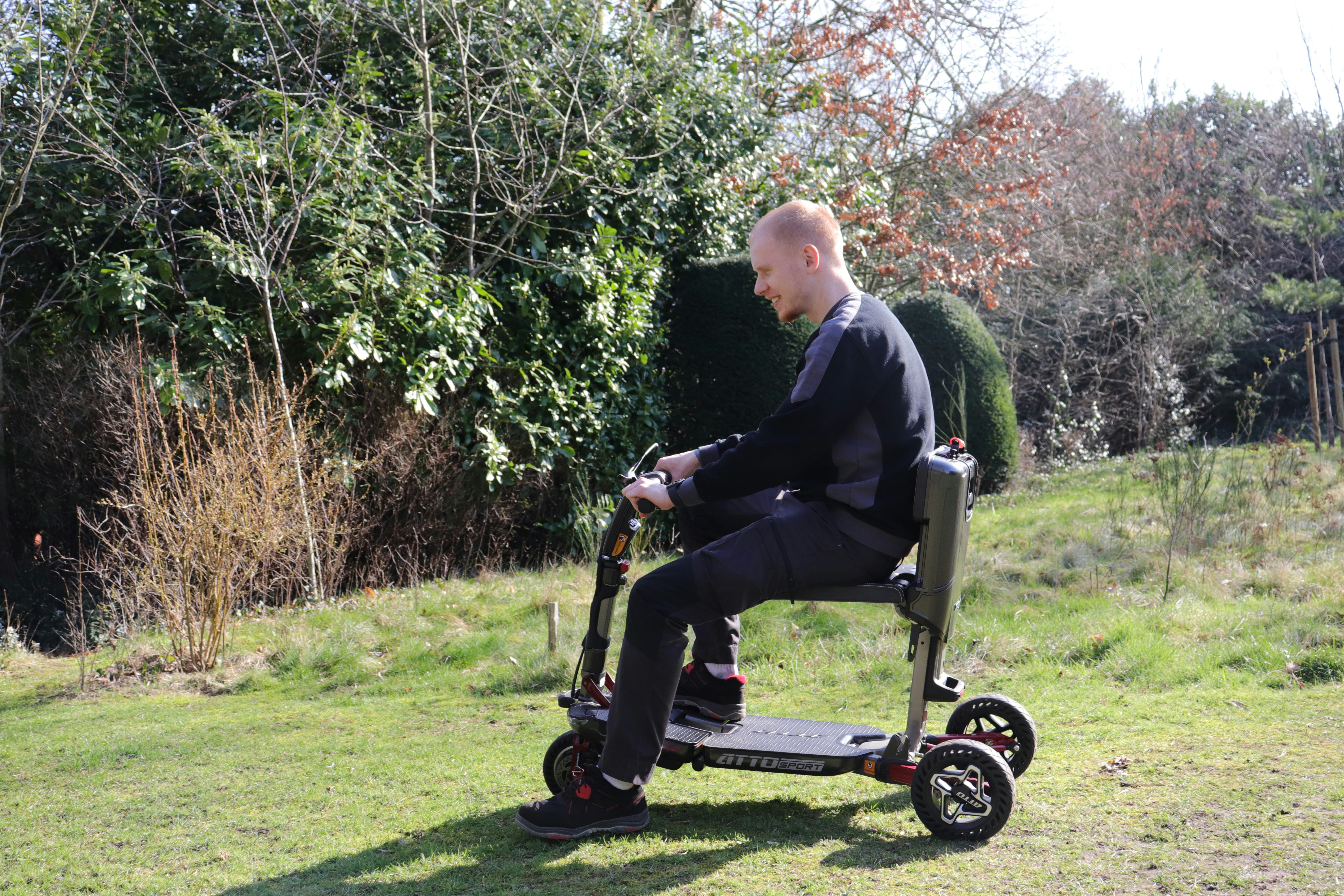 Man on a compact electric scooter enjoys a sunlit garden stroll