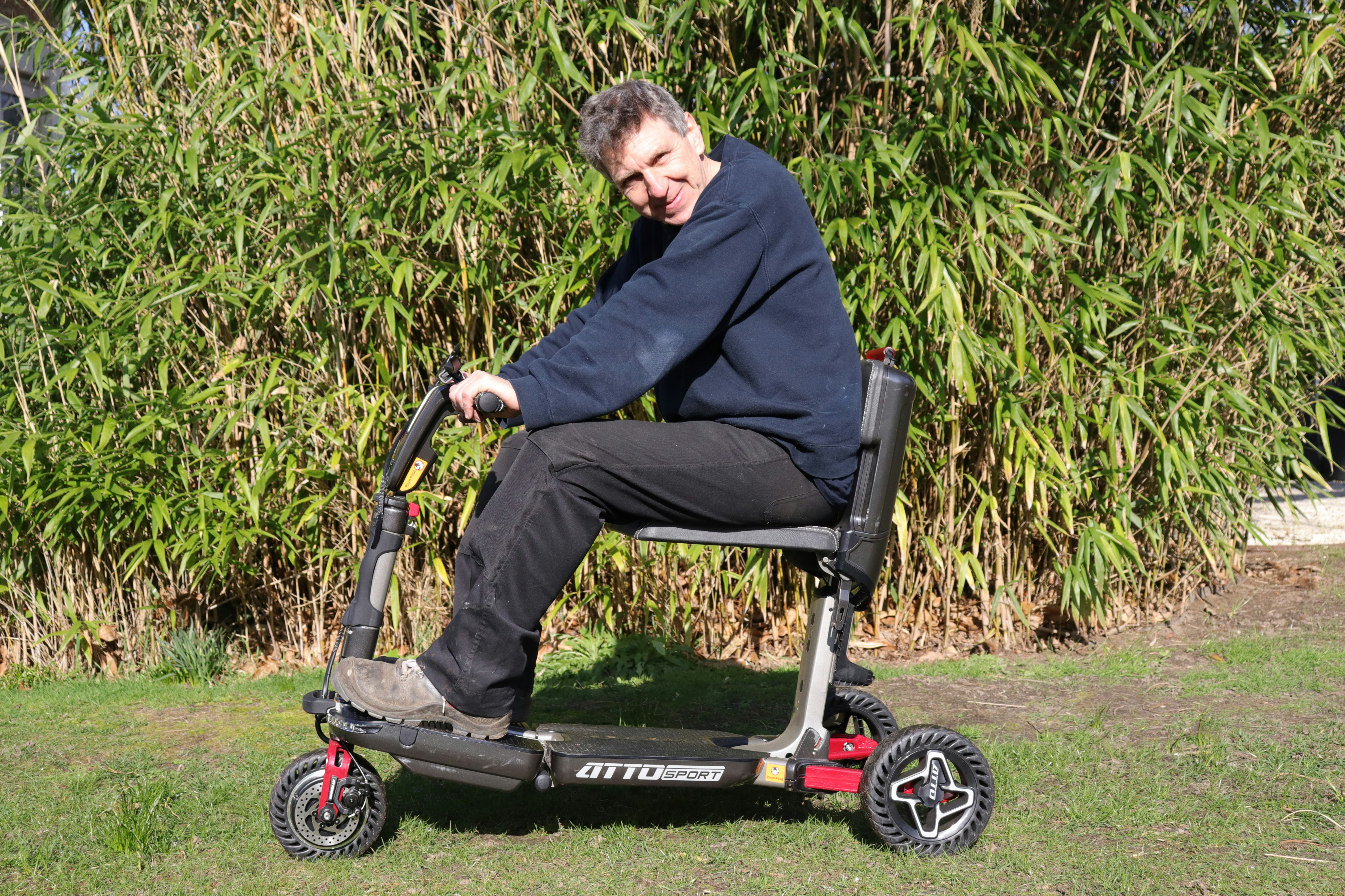 Gentleman on a compact scooter turns toward the garden hedge