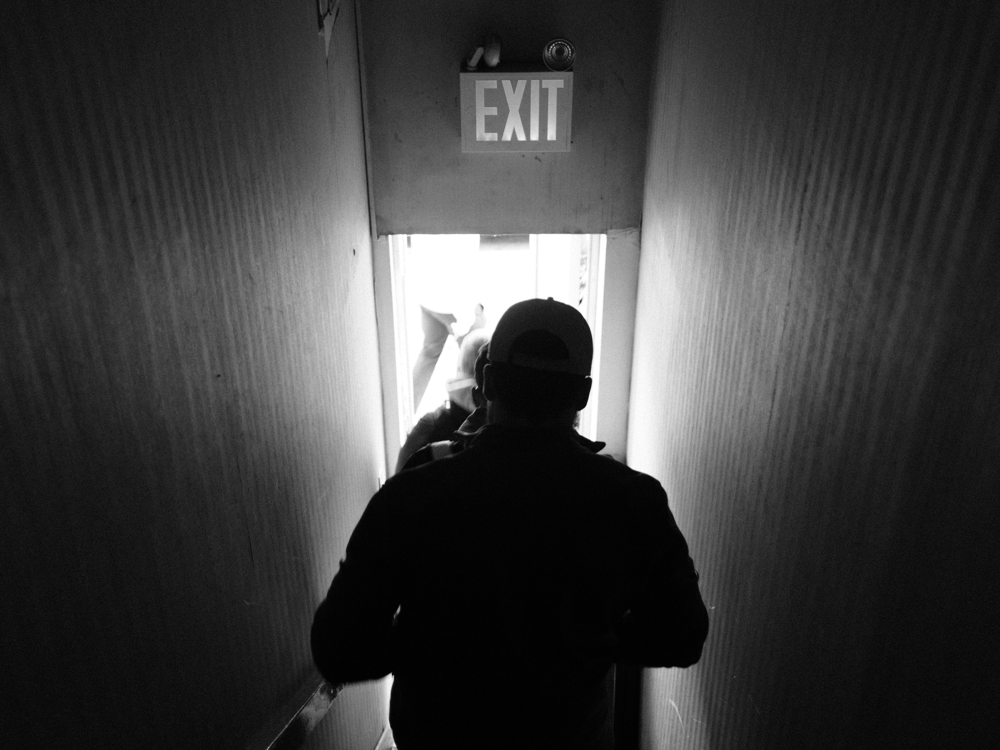 Exit Corridor: Silhouetted Figure Reaching Toward Light