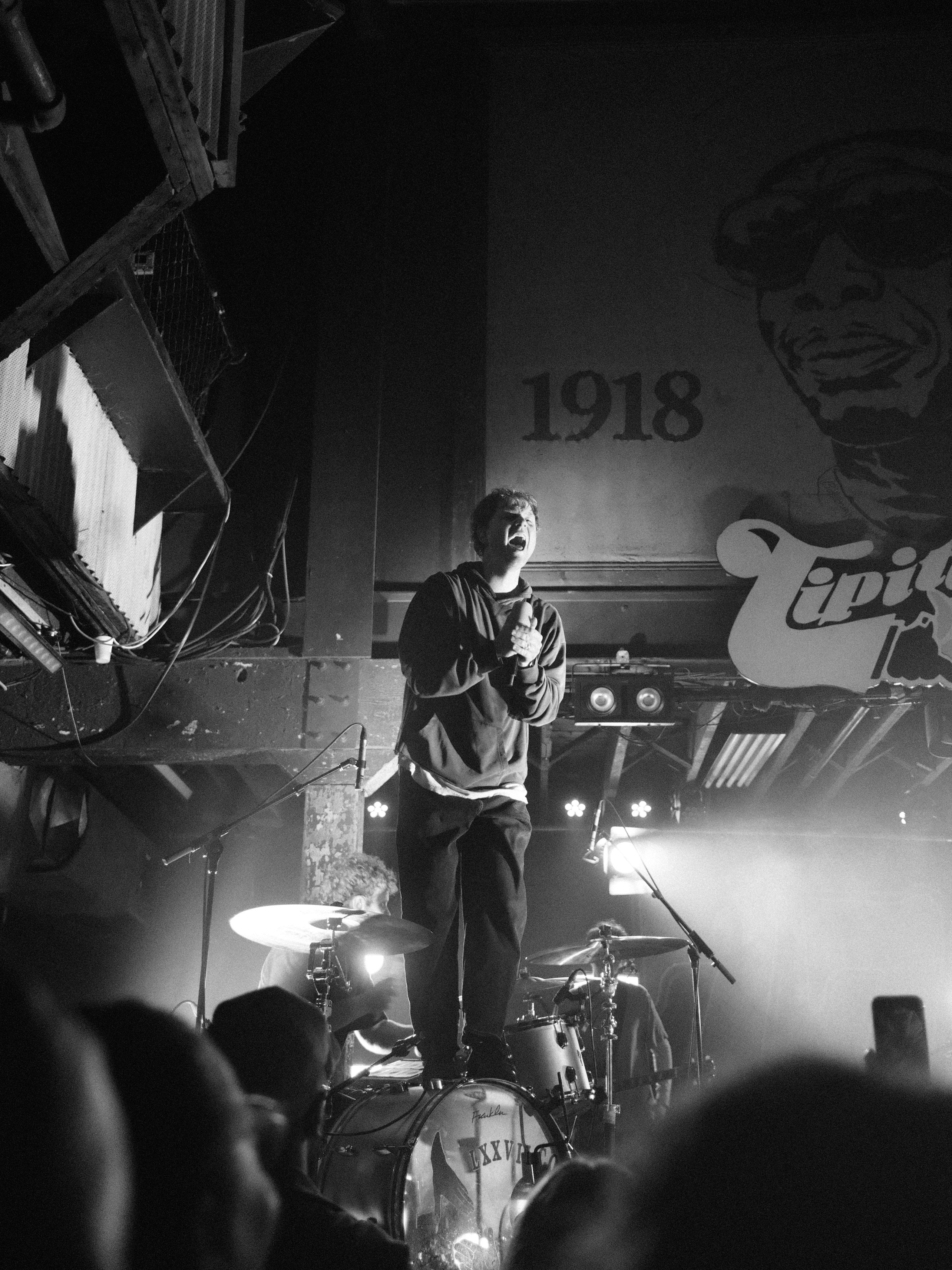 Center Stage: The Vocalist Surfaces Above the Drums in Dim Club Lighting