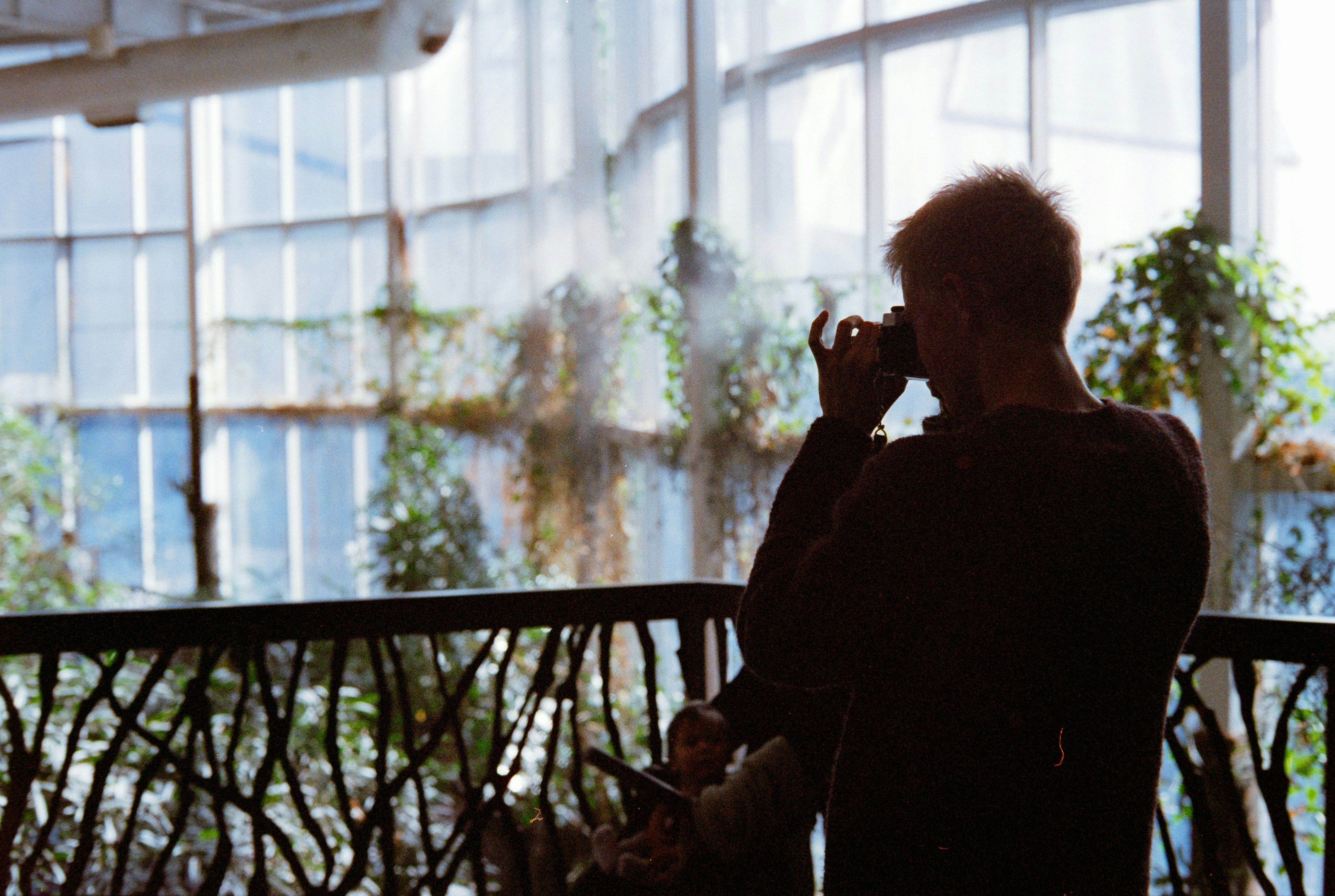 Silhouette of a Photographer in a Glasshouse Balcony