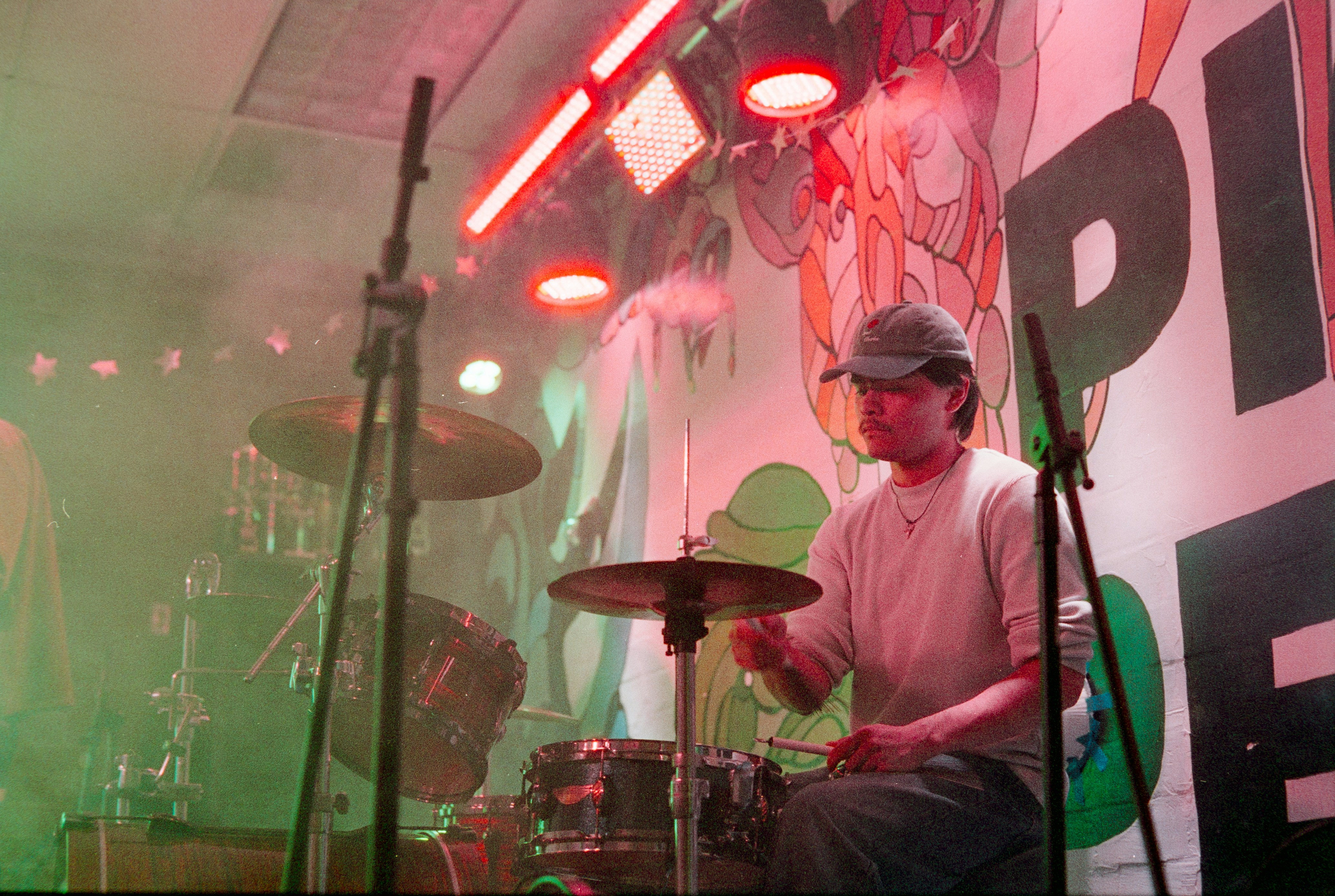 Green haze on stage: drummer in mid-beat under neon lights