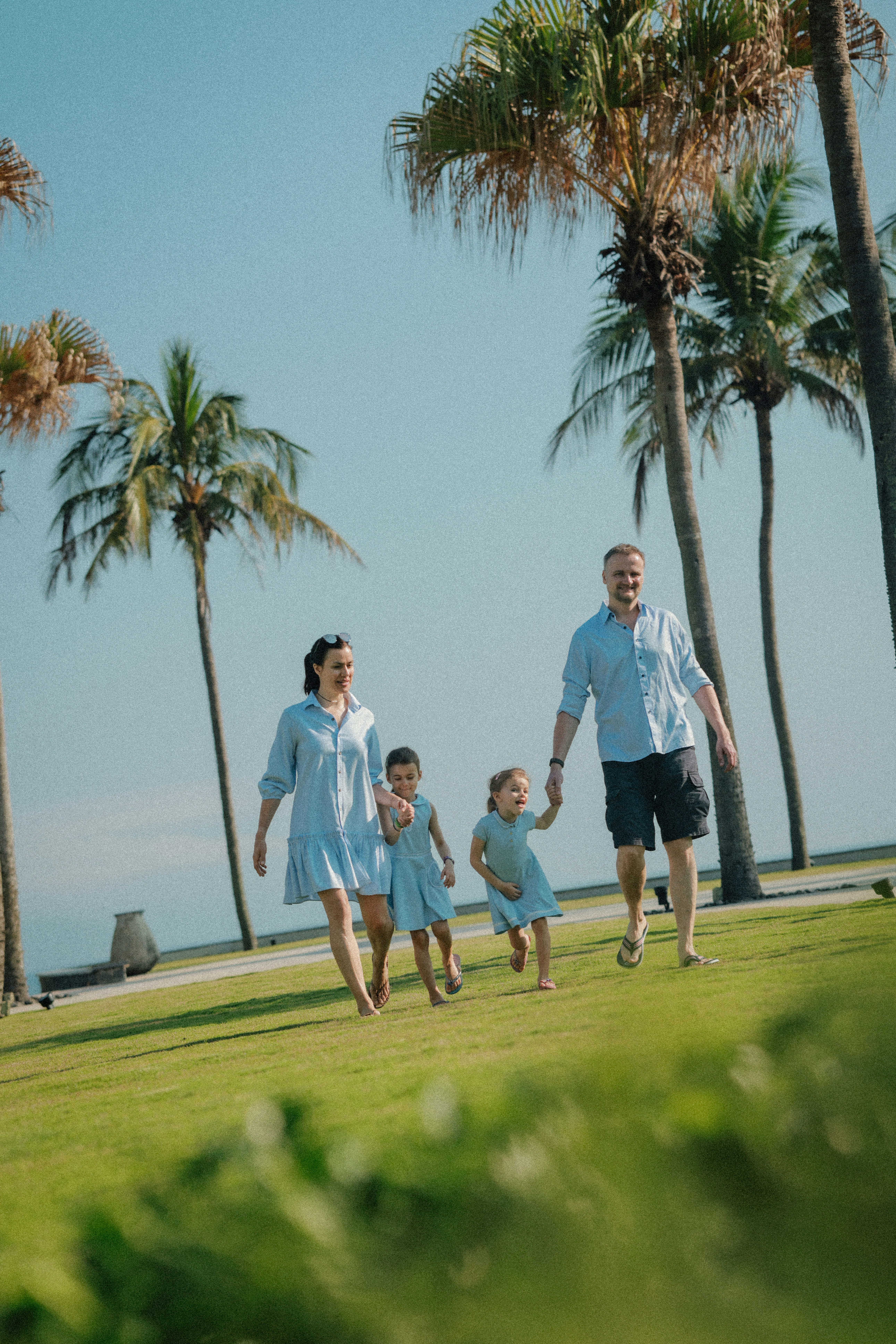 Sunlit seaside stroll: a family framed by palm silhouettes