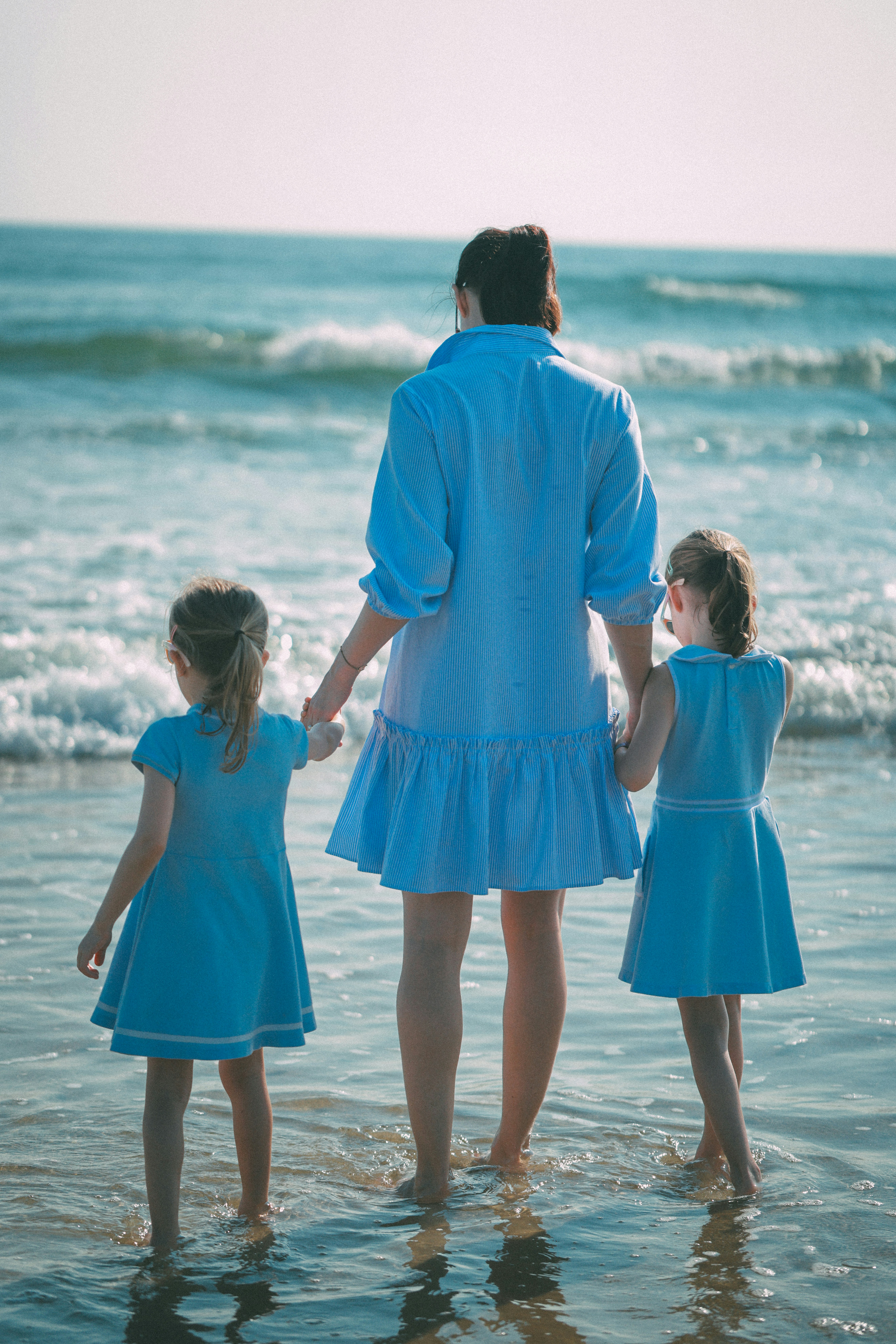 Blue Dawn at the Shore: A Mother and Girls Stand at the Sea