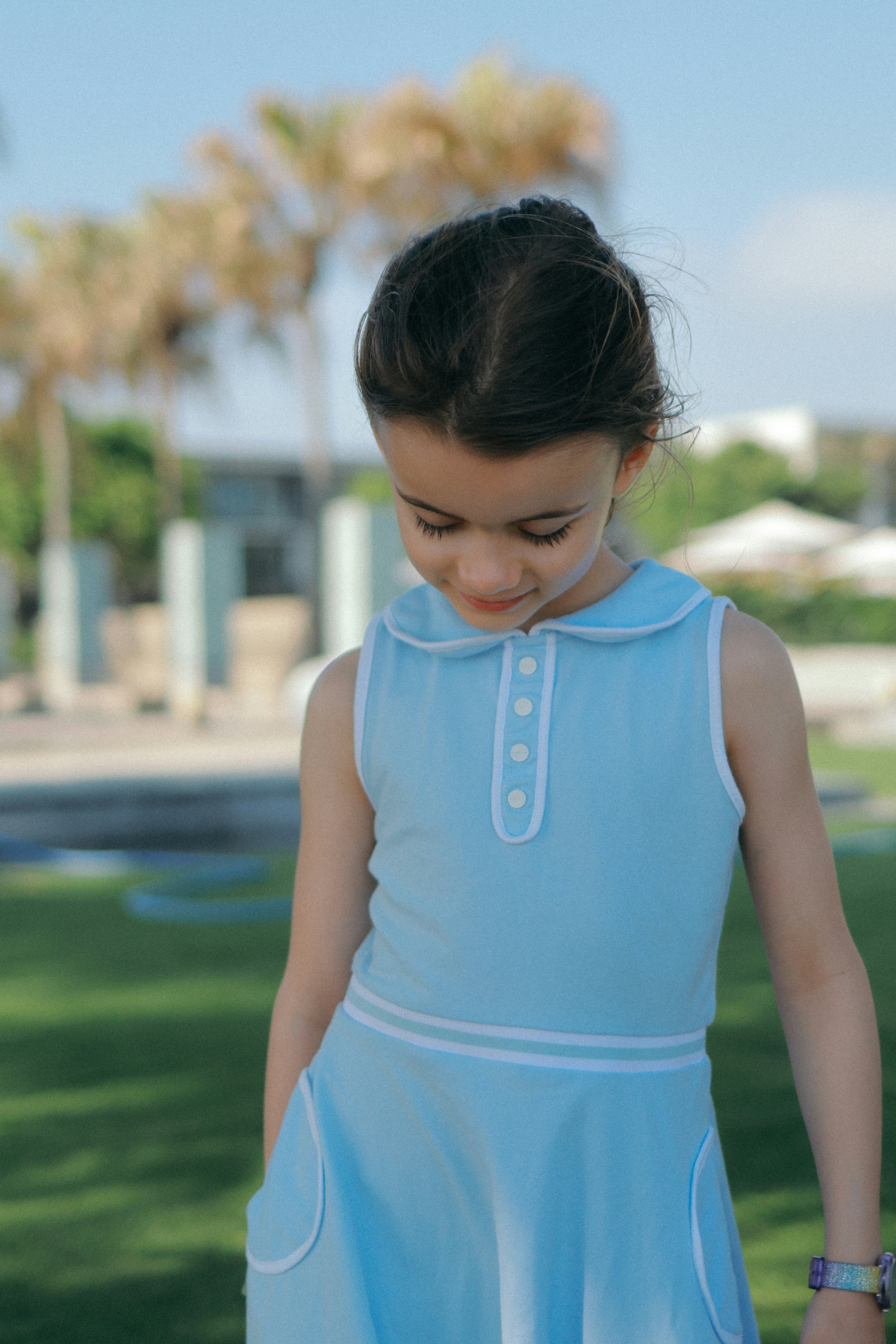 A young girl in a blue dress outdoors